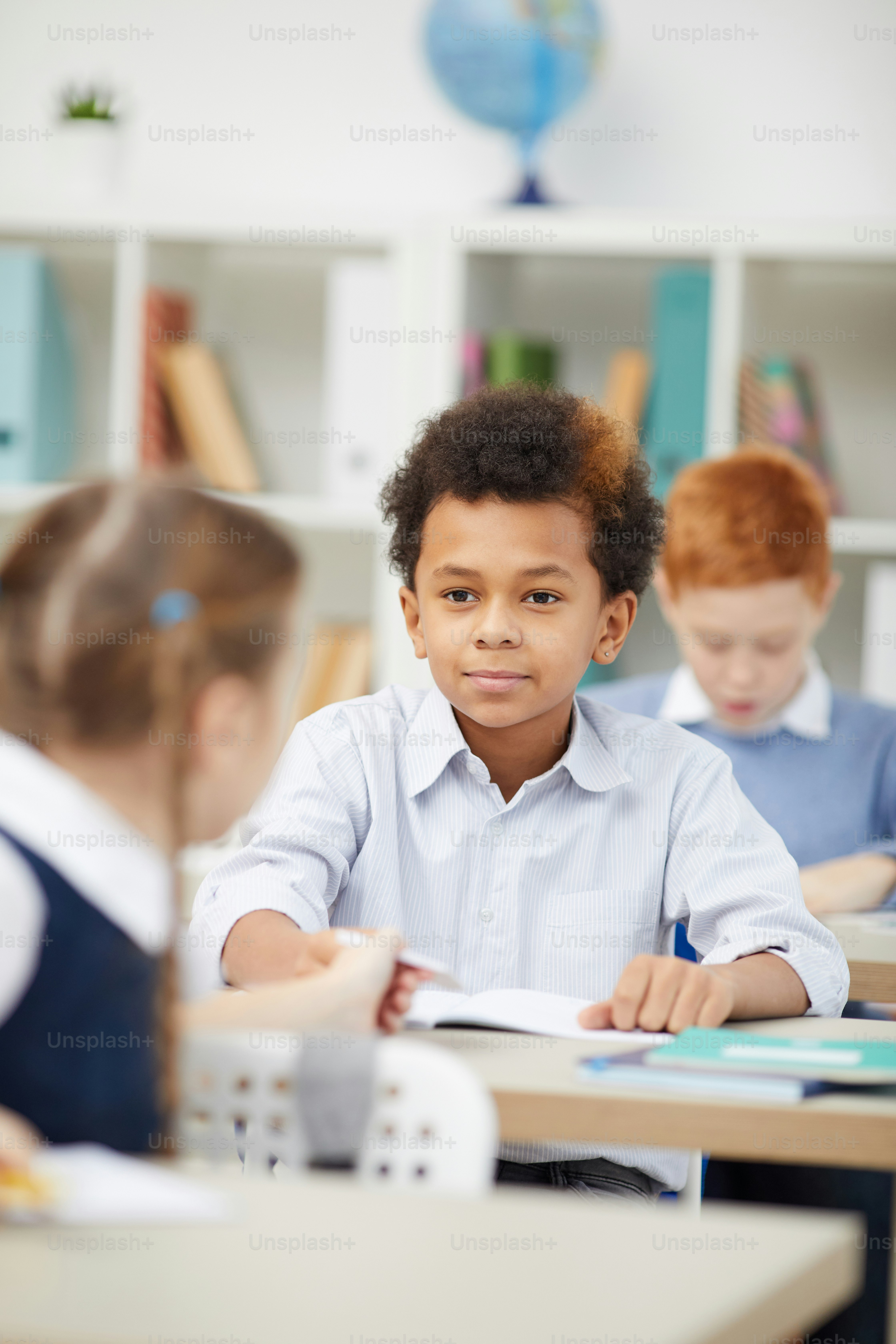 Young teacher in eyeglasses holding clipboard and walking along the ...