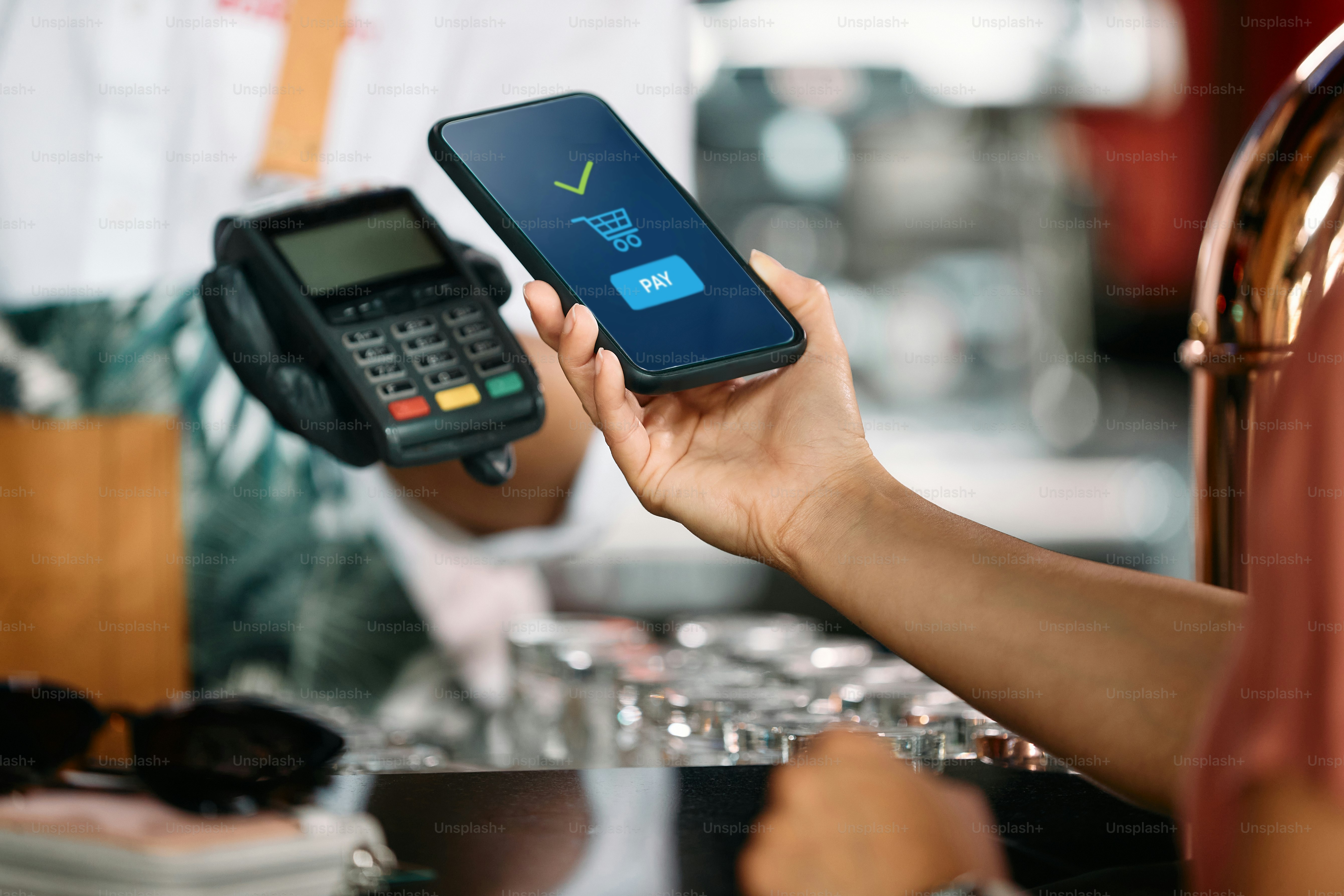 Close-up of woman using smart phone while making contactless payment in ...