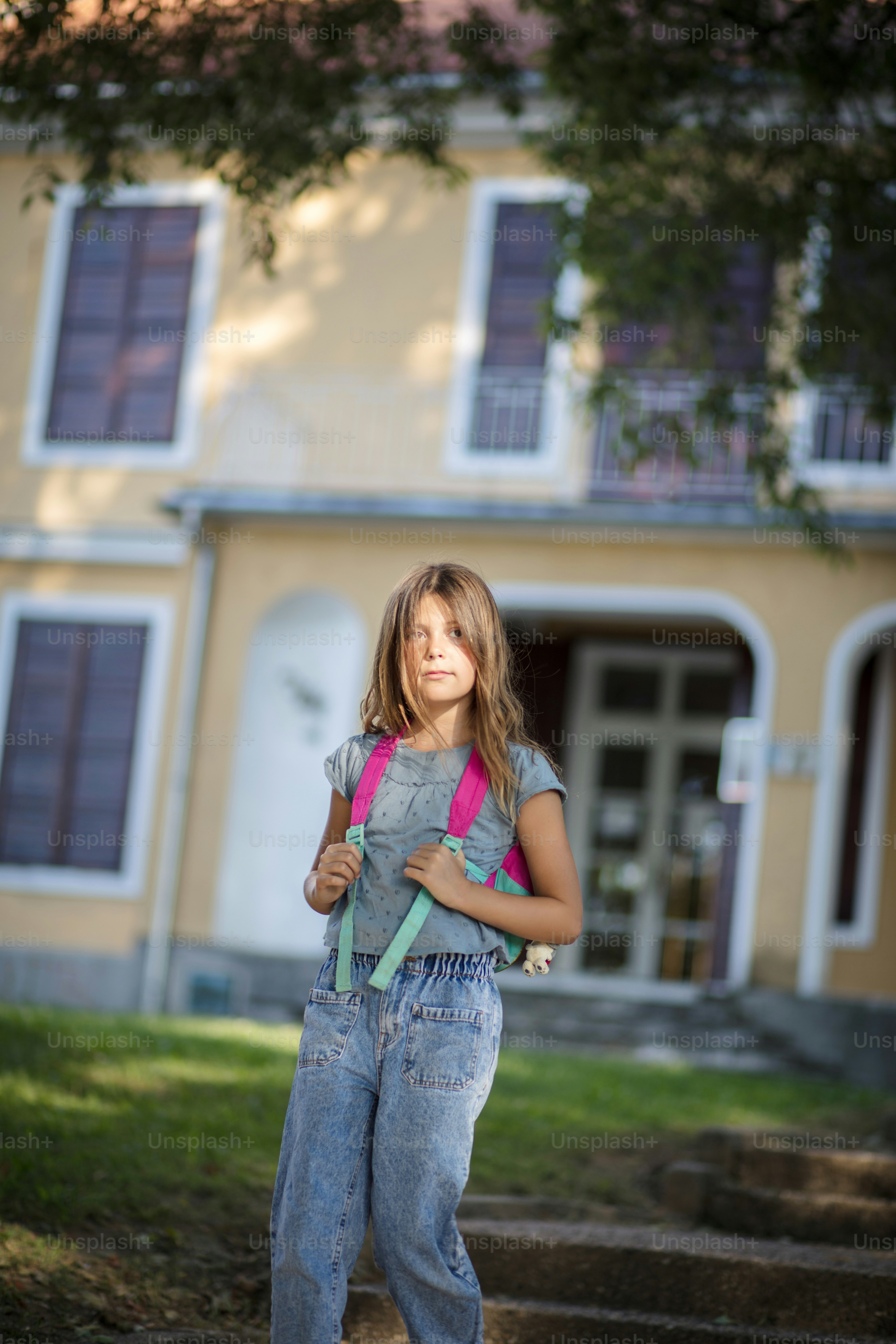 The end of the school day. Little girl leaving school. Looking at ...