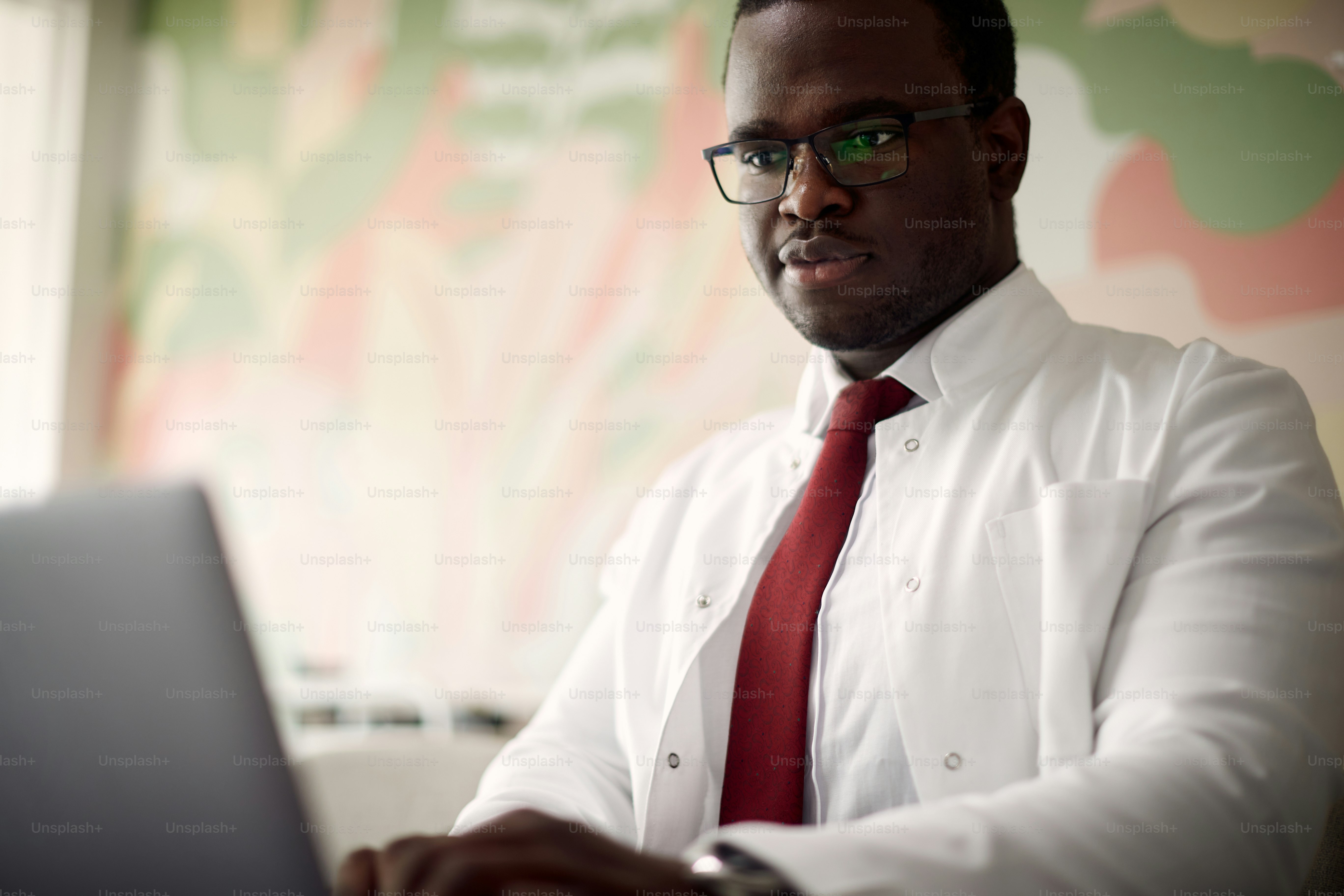 African American general practitioner using laptop while working at ...
