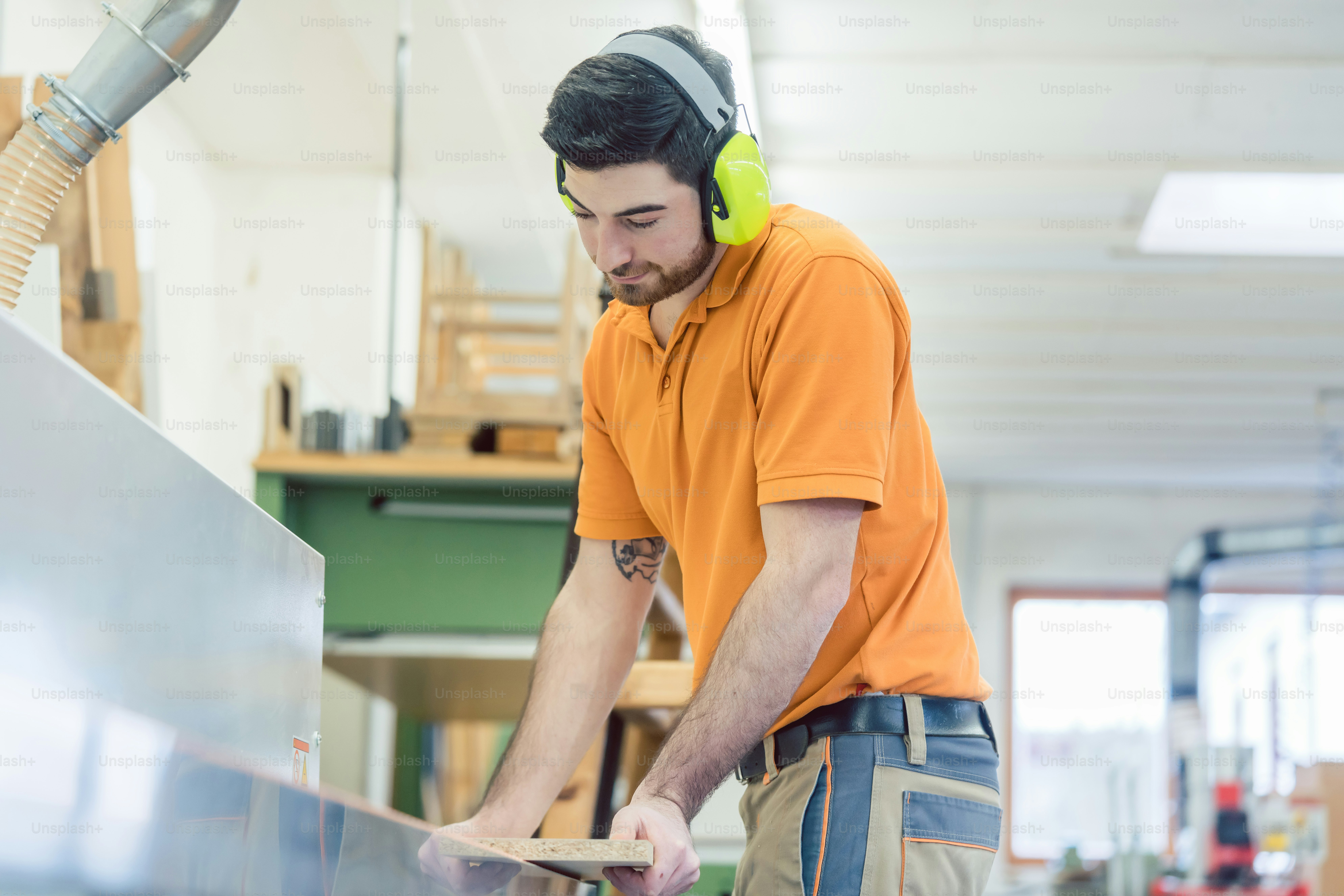 Carpenter working in furniture factory on computer controlled machine ...