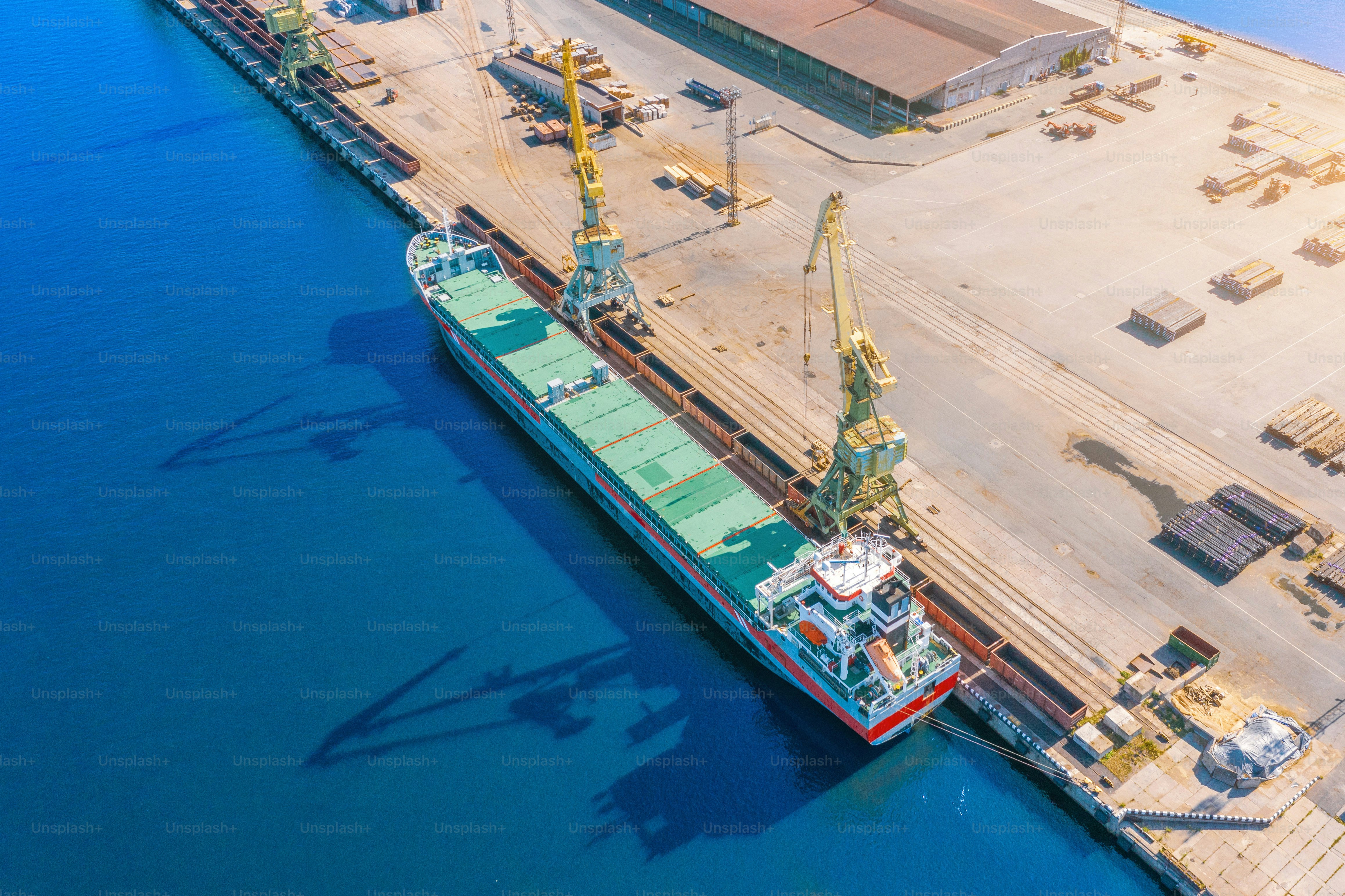 Aerial top view huge cargo ship moored at the pier at the port, loading ...