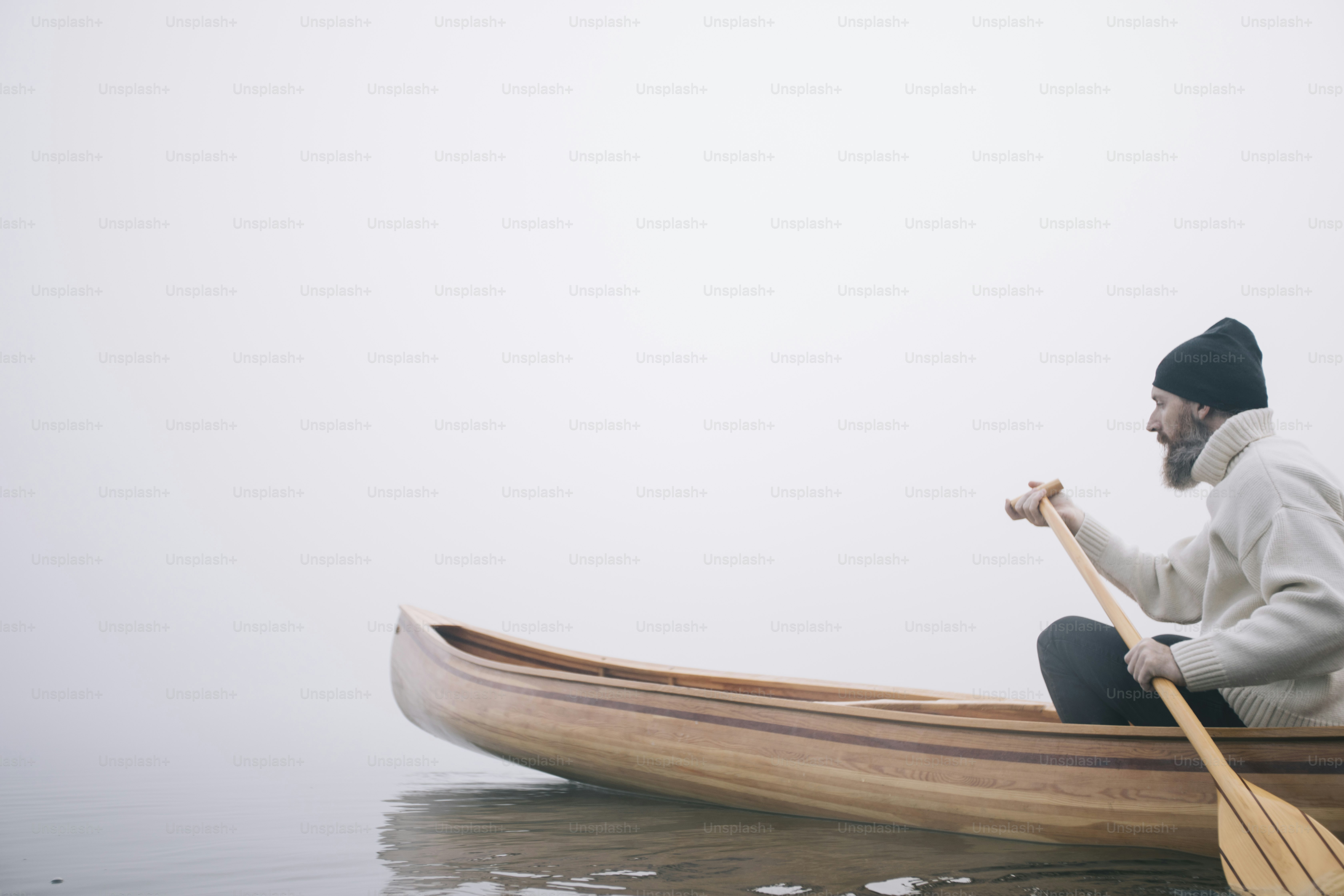 Vista lateral del hombre remando en canoa en invierno, espacio de copia ...