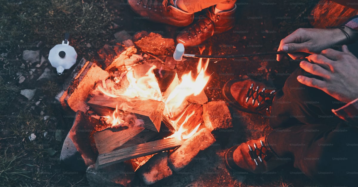 산에서 캠핑하는 동안 모닥불 위에서 마시멜로를 굽는 젊은 커플의 평면도를 닫습니다 사진 Unsplash의 우크라이나 이미지