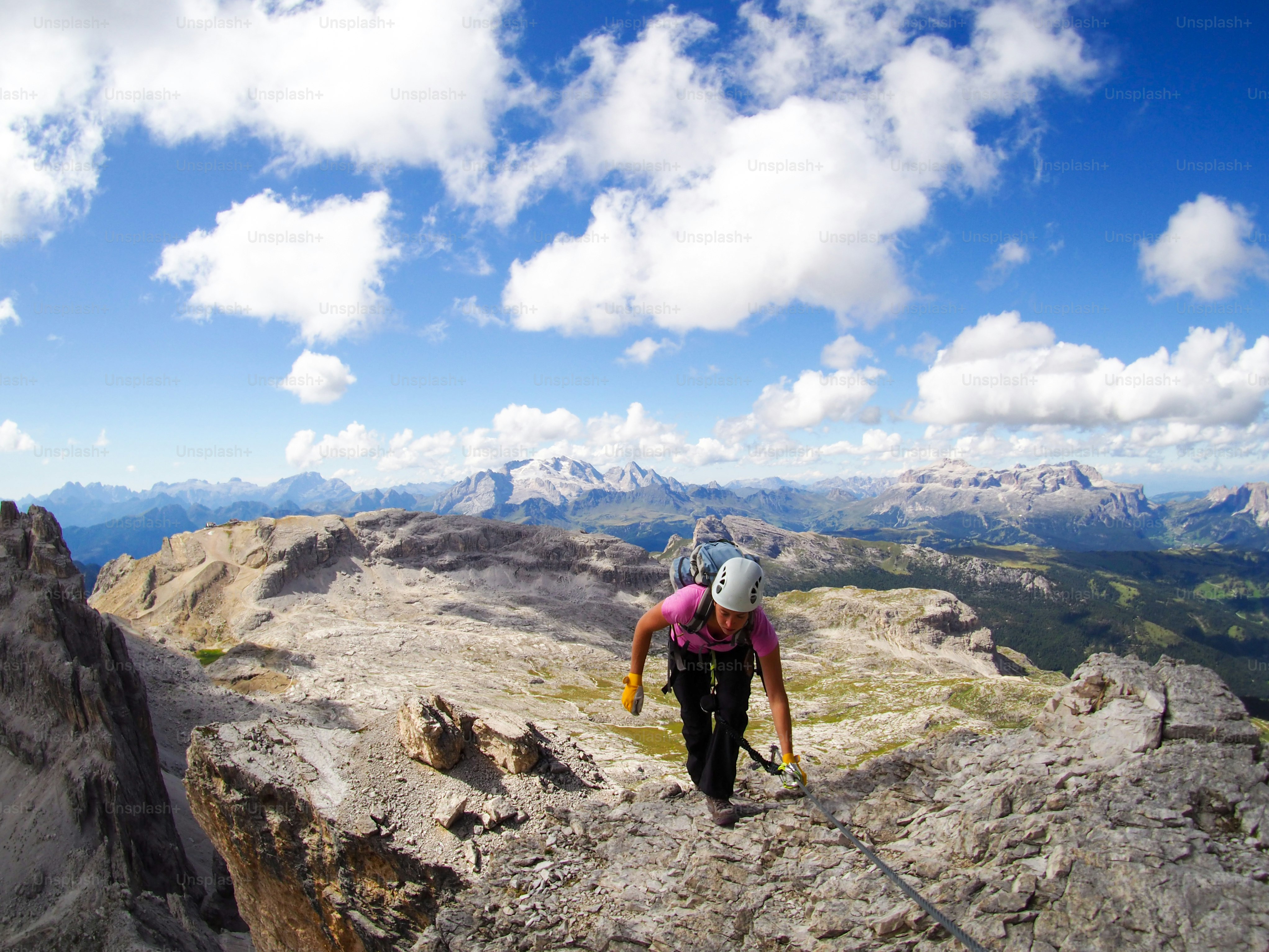 Eine Bergsteigerin erreicht den Gipfel mit toller Dolomitenlandschaft ...