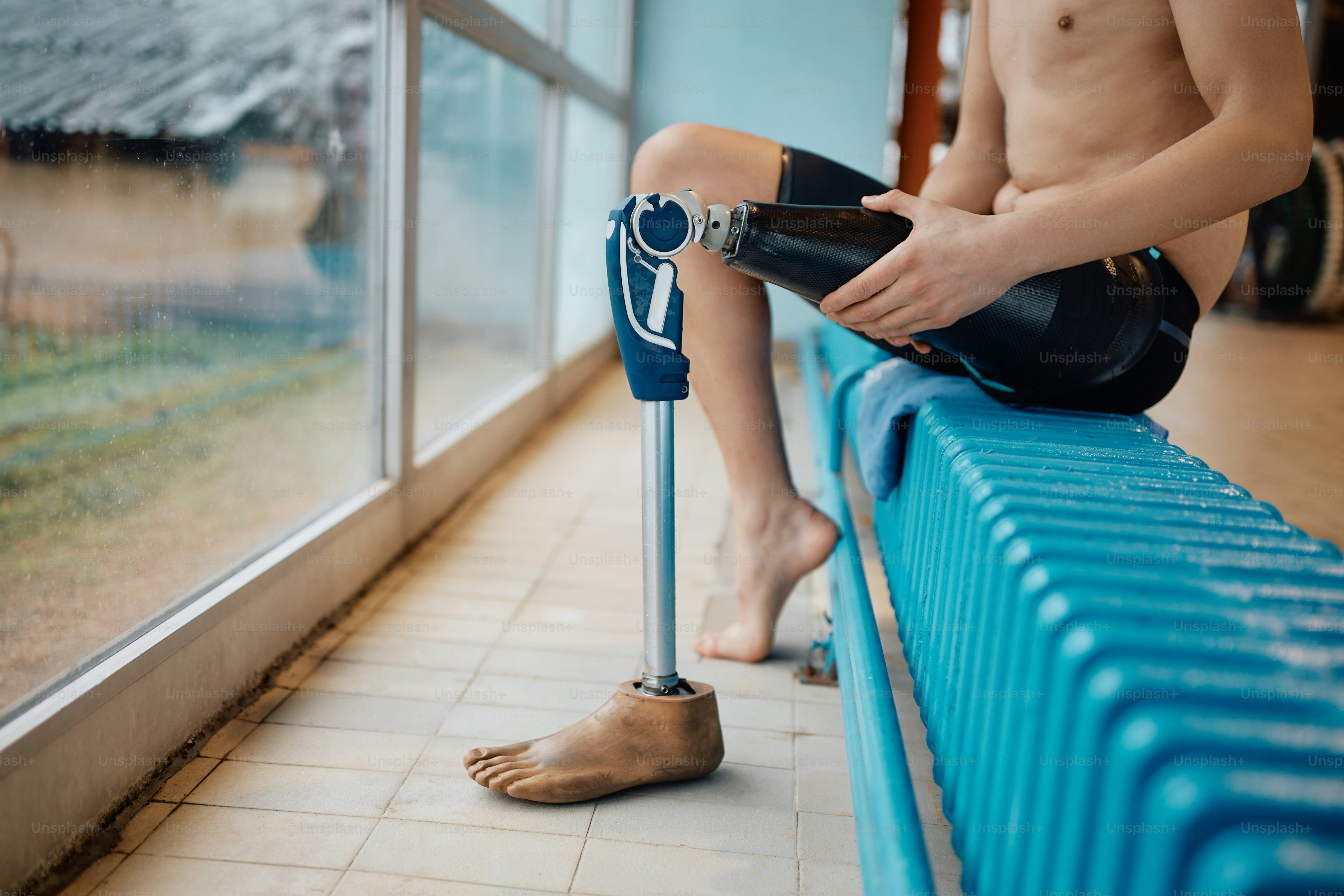 Unrecognizable swimmer with disability adjusting his artificial leg ...