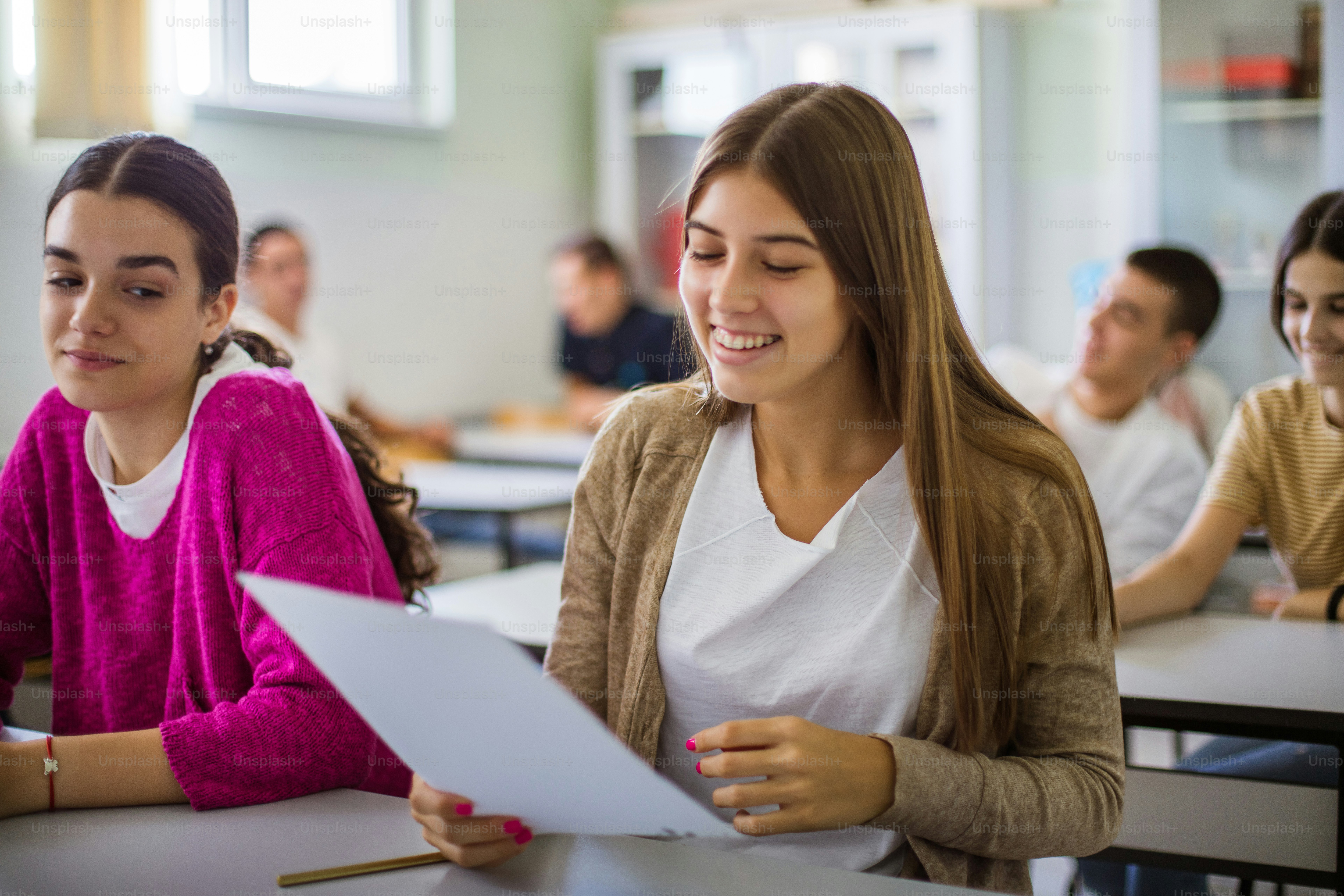Smiling student girl holding control task. Students in classroom. Focus ...