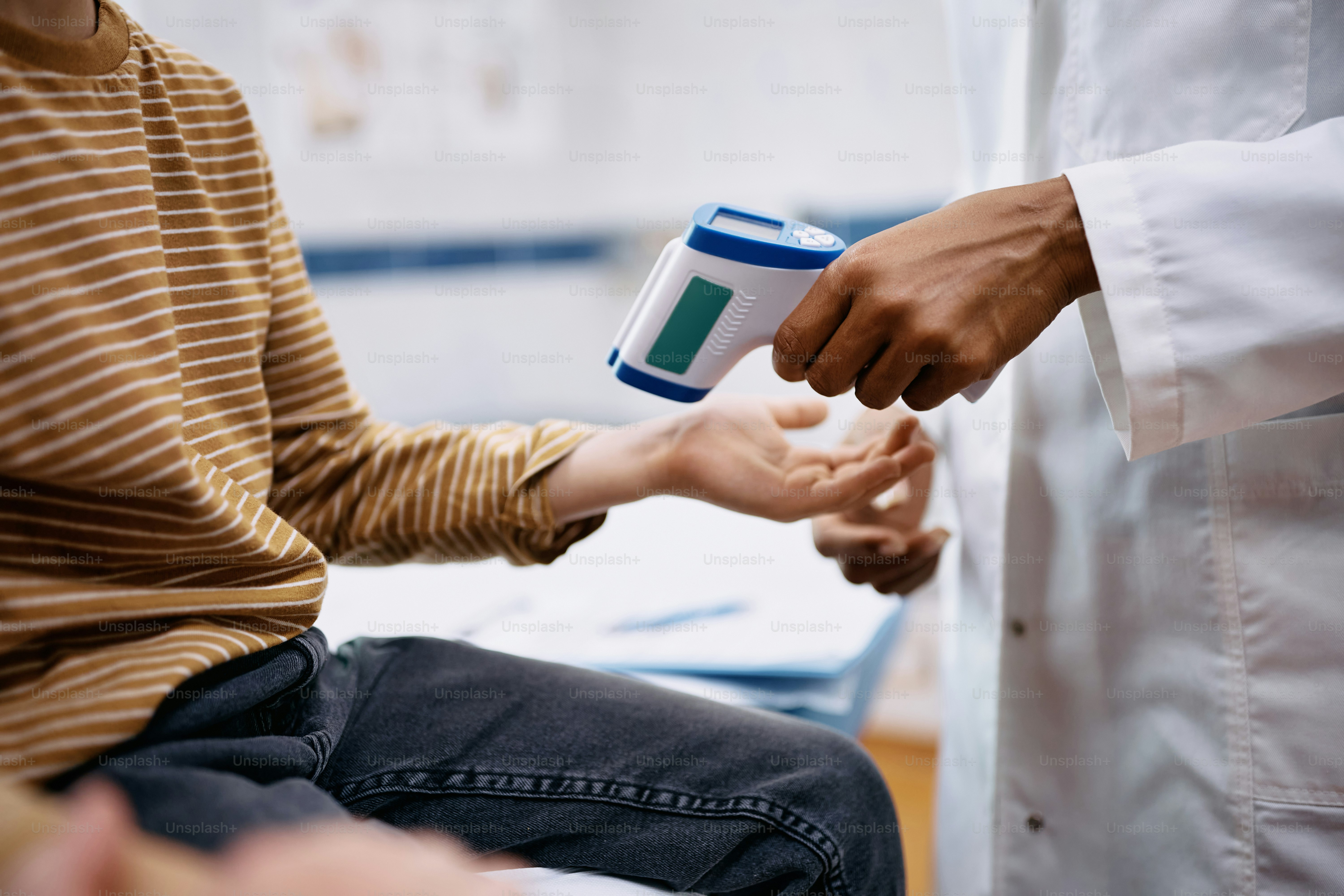 Gros plan d’un médecin utilisant un thermomètre infrarouge tout en ...