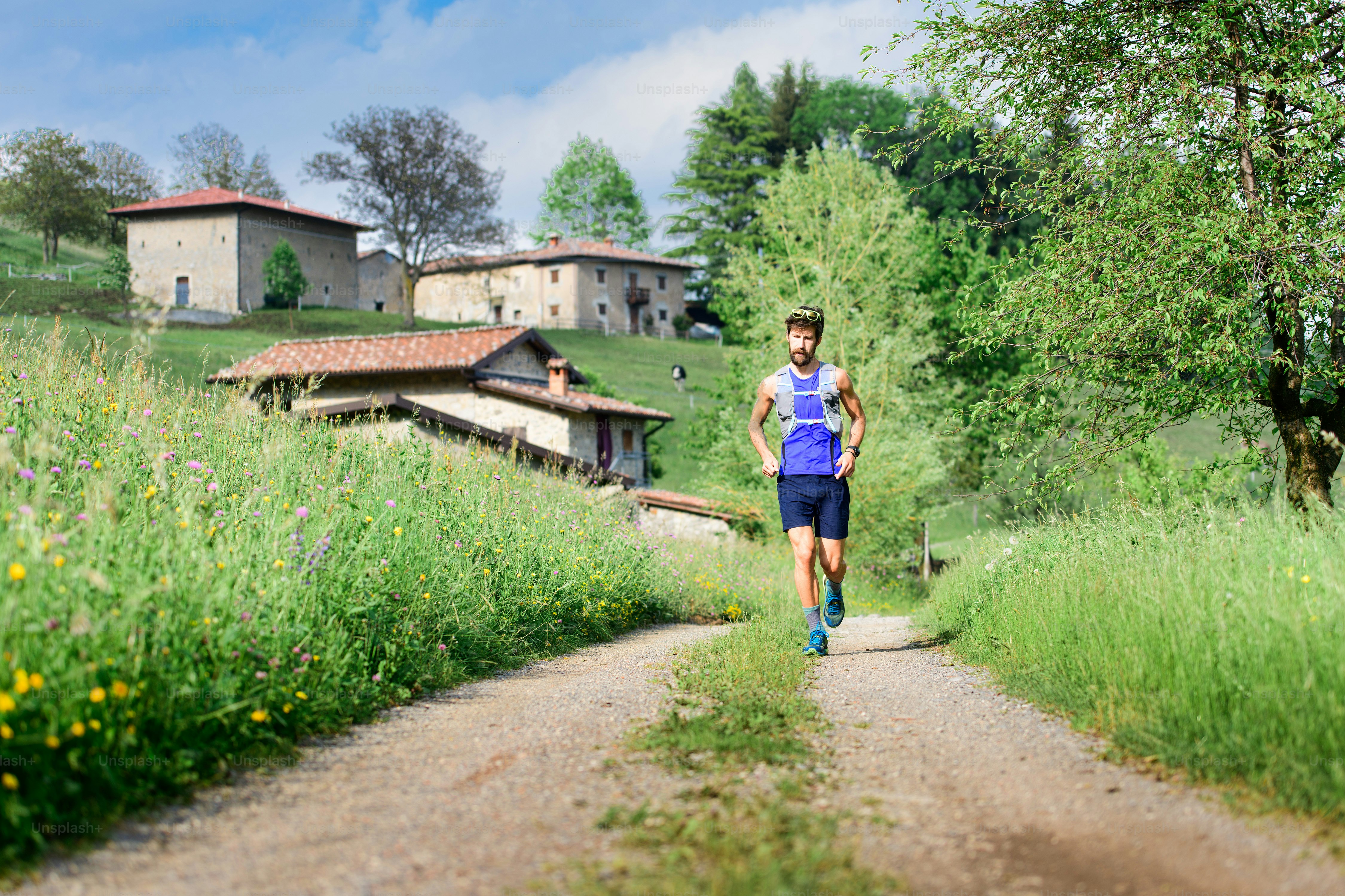 Young athlete runs in rural hill landscape photo – Running Image on ...