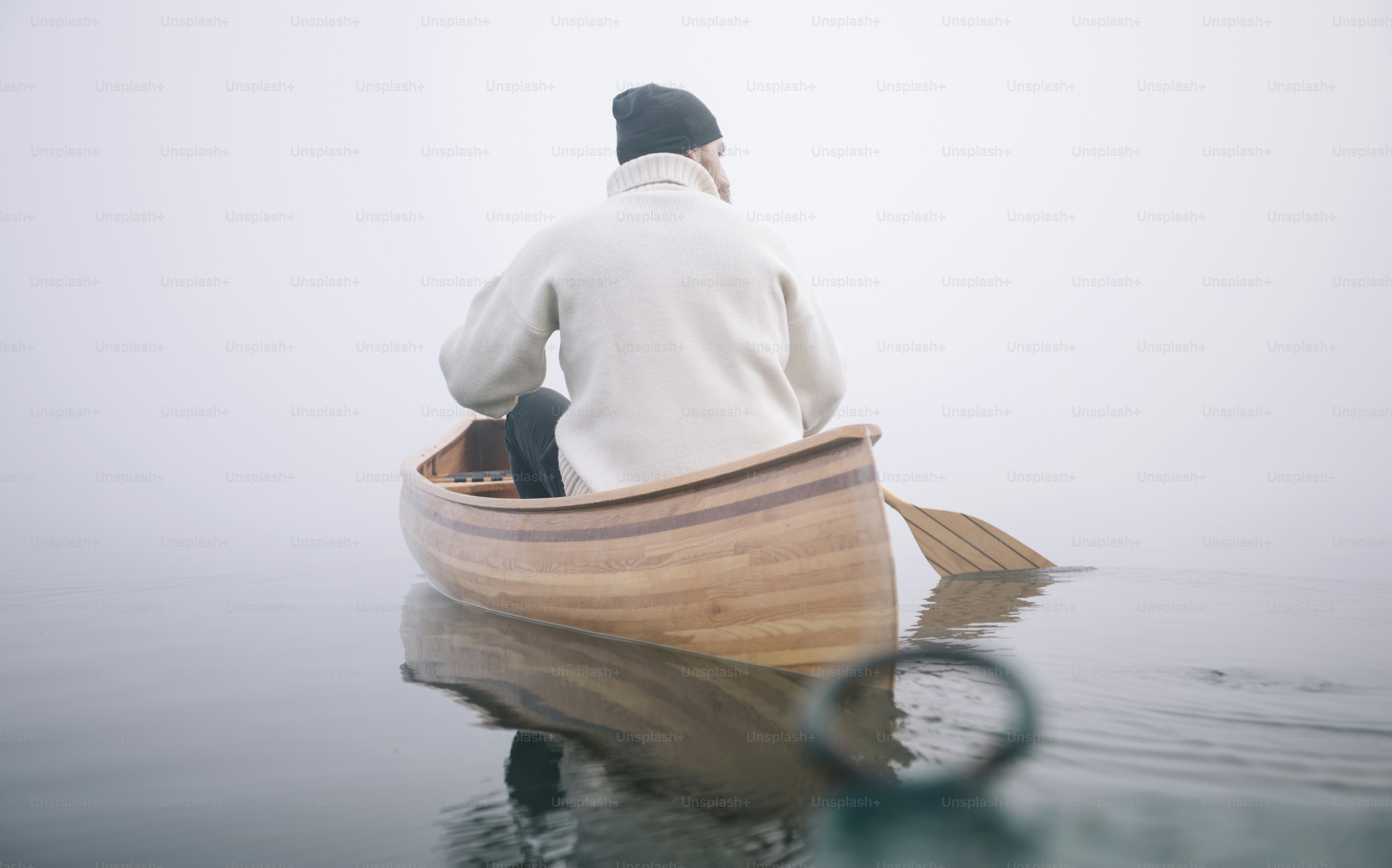 Rear view of man paddling canoe in the winter, copy space. photo – Rear ...