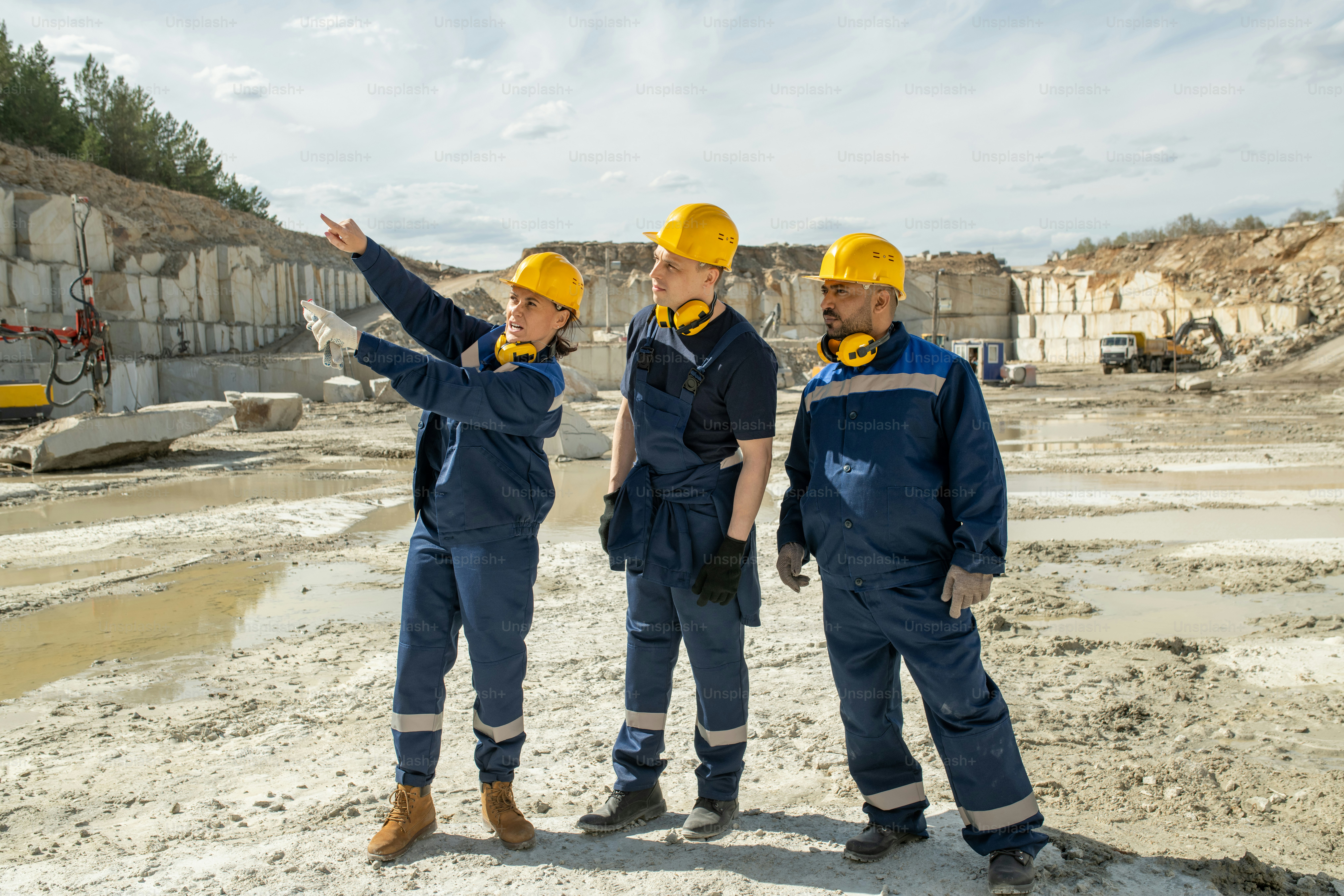Mature female miner pointing at one of building places while talking to ...