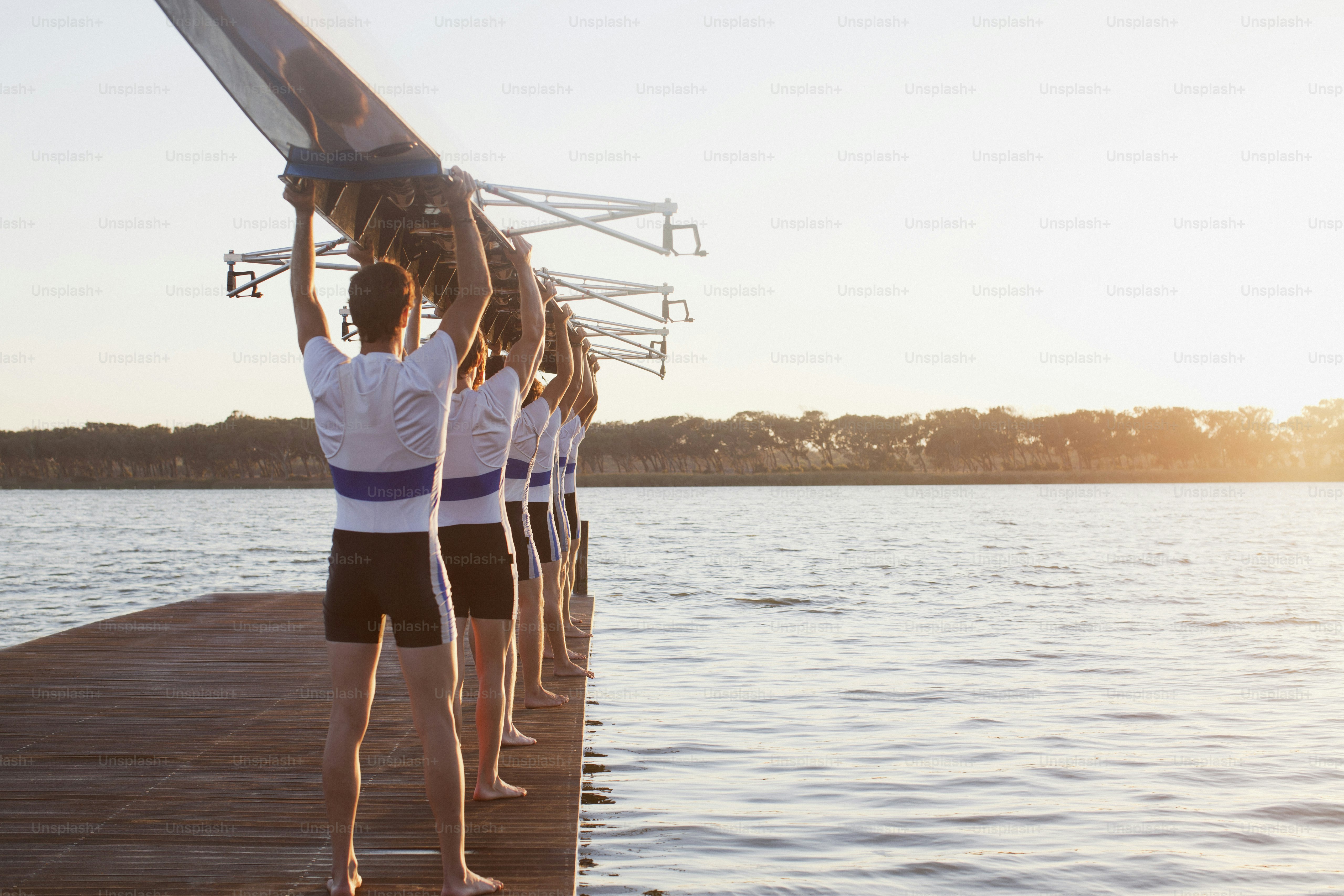 A group of people rowing a long boat in the water photo – Men Image on ...