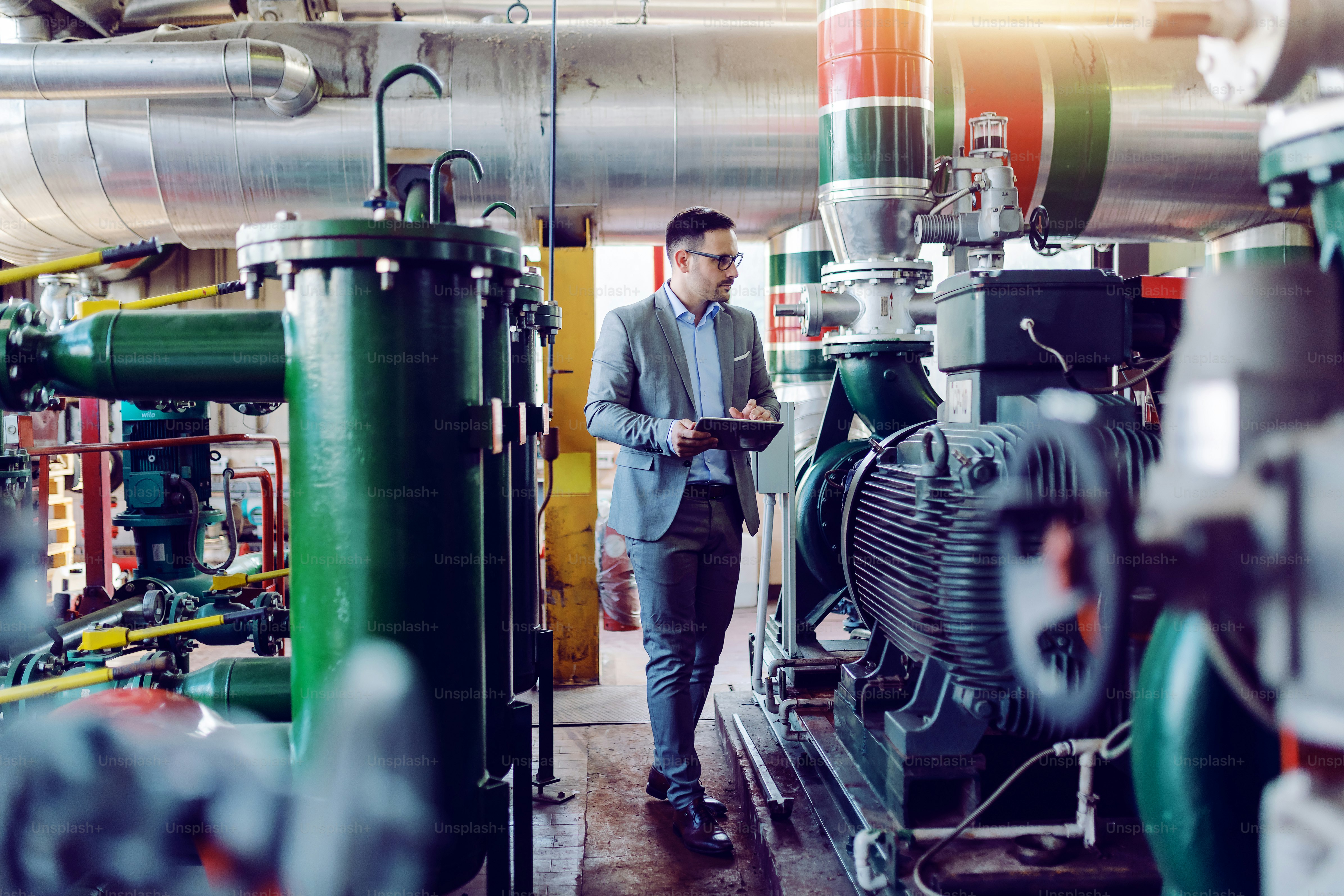 Handsome caucasian manager in gray suit and with helmet on head using ...