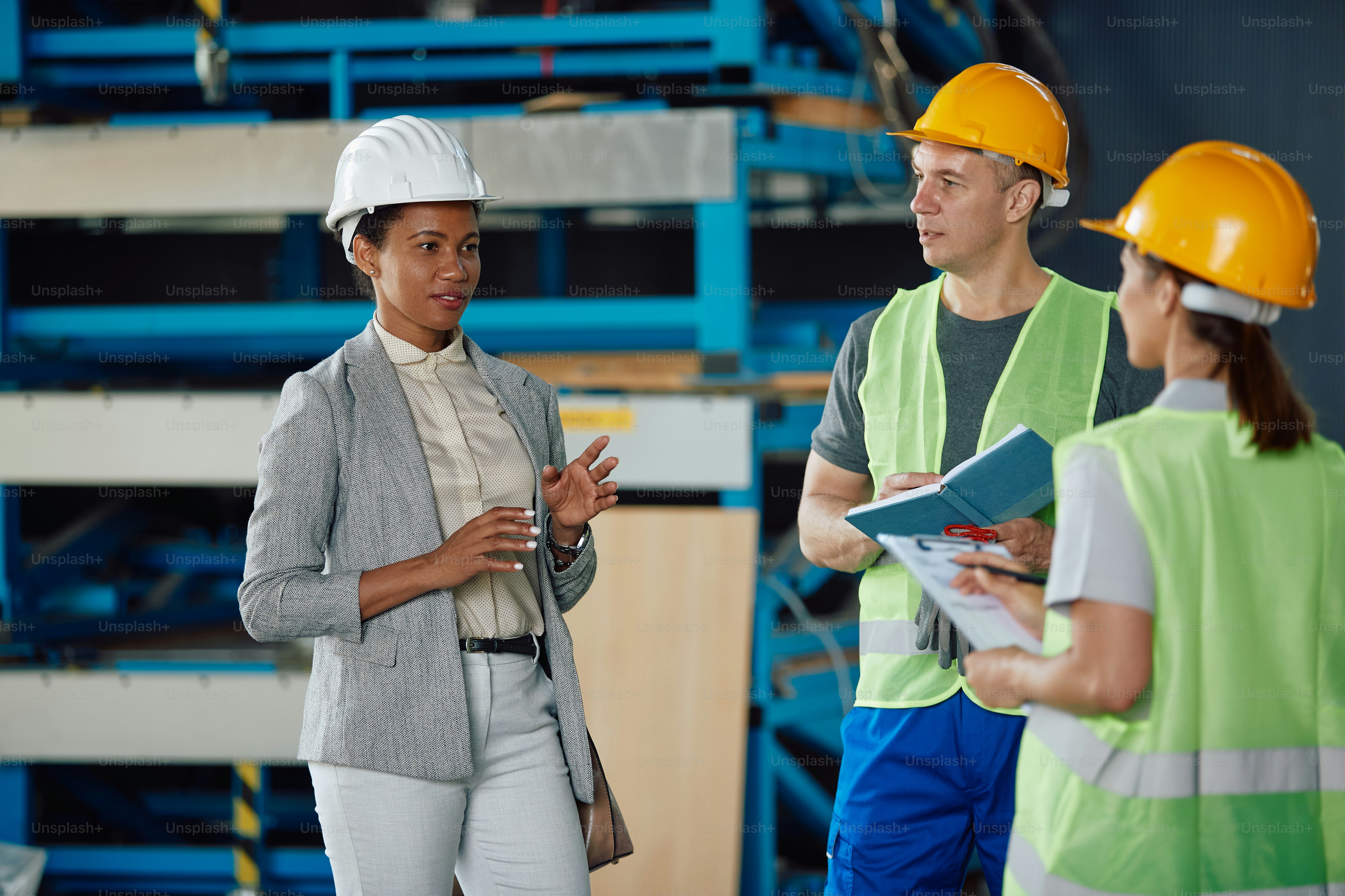 Black female supervisor communicating with warehouse workers at storage ...