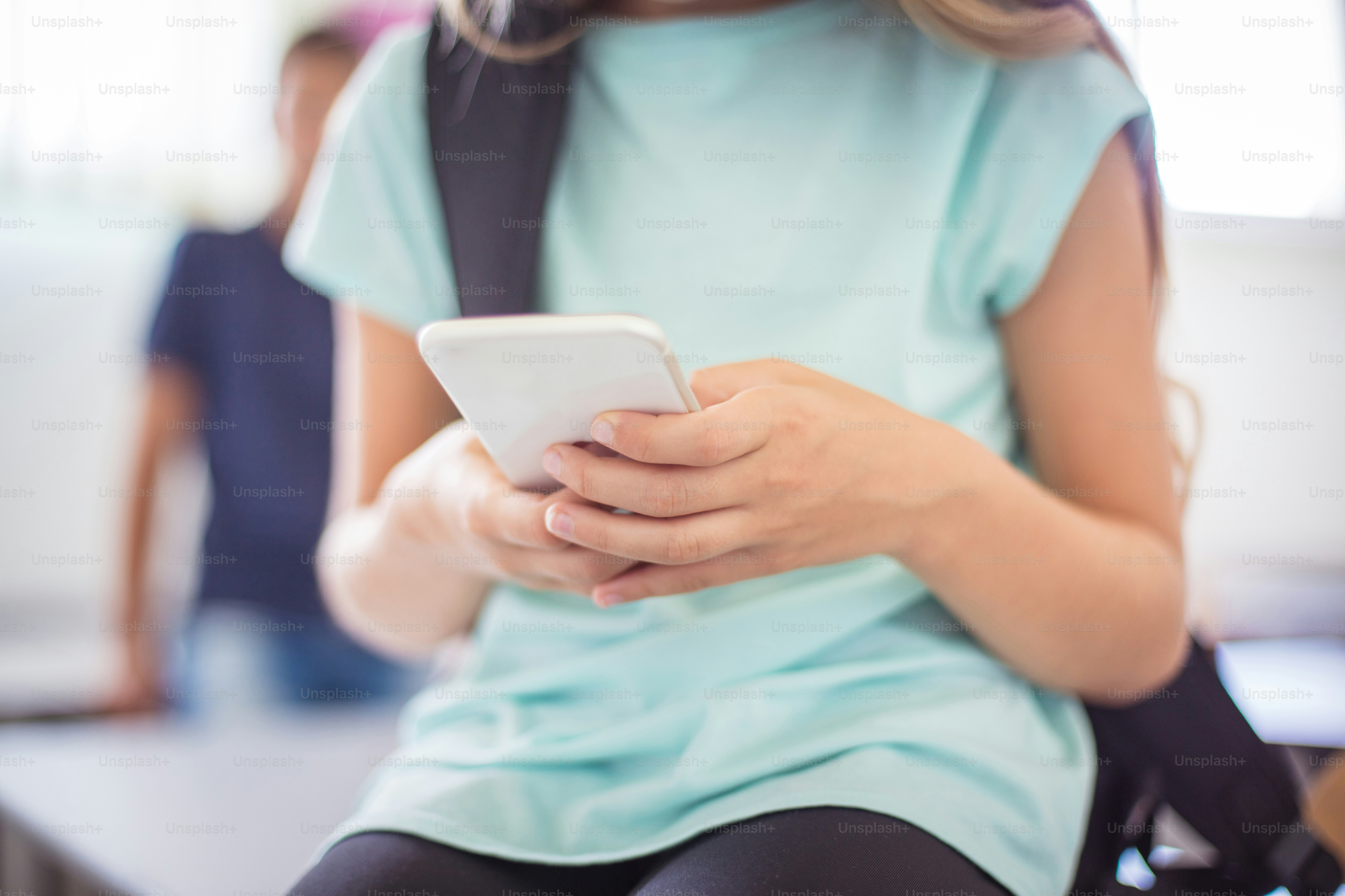 School girl using phone in classroom. Focus is on foreground. photo ...