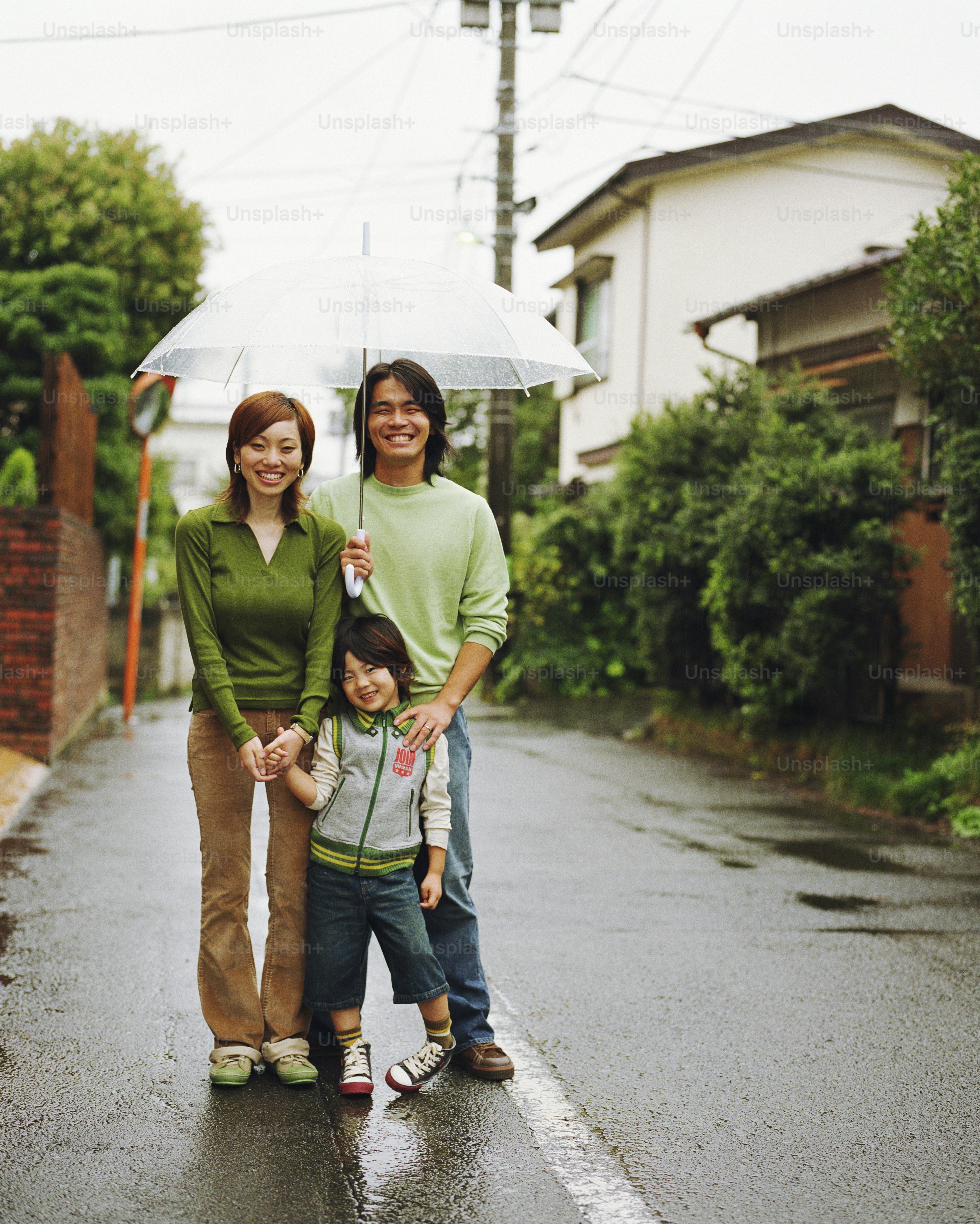 Parents and son (4-6) standing under umbrella, smiling, portrait photo ...