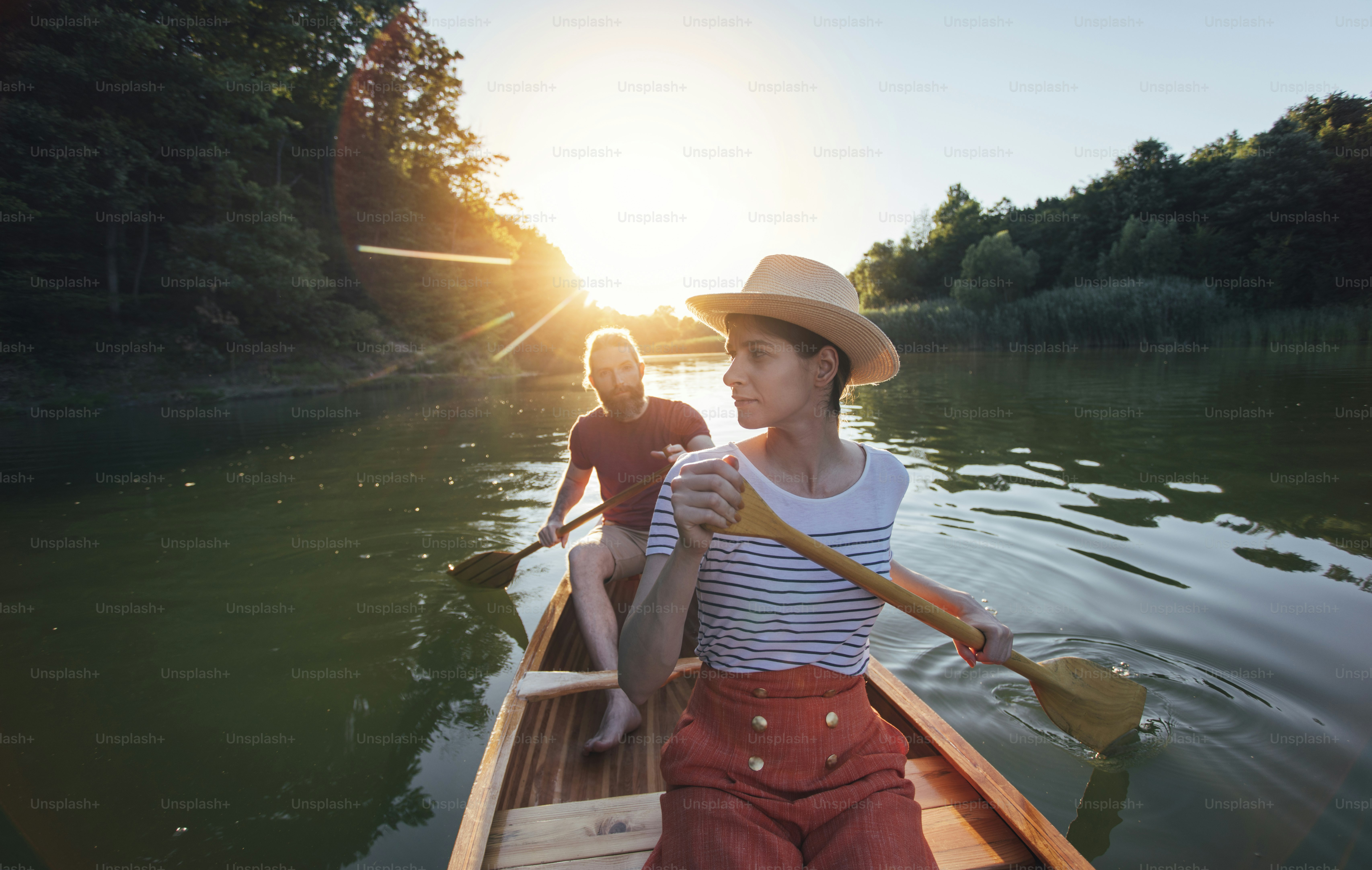 Couple enjoy paddling canoe on the sunset lake. Woman and man on a ...