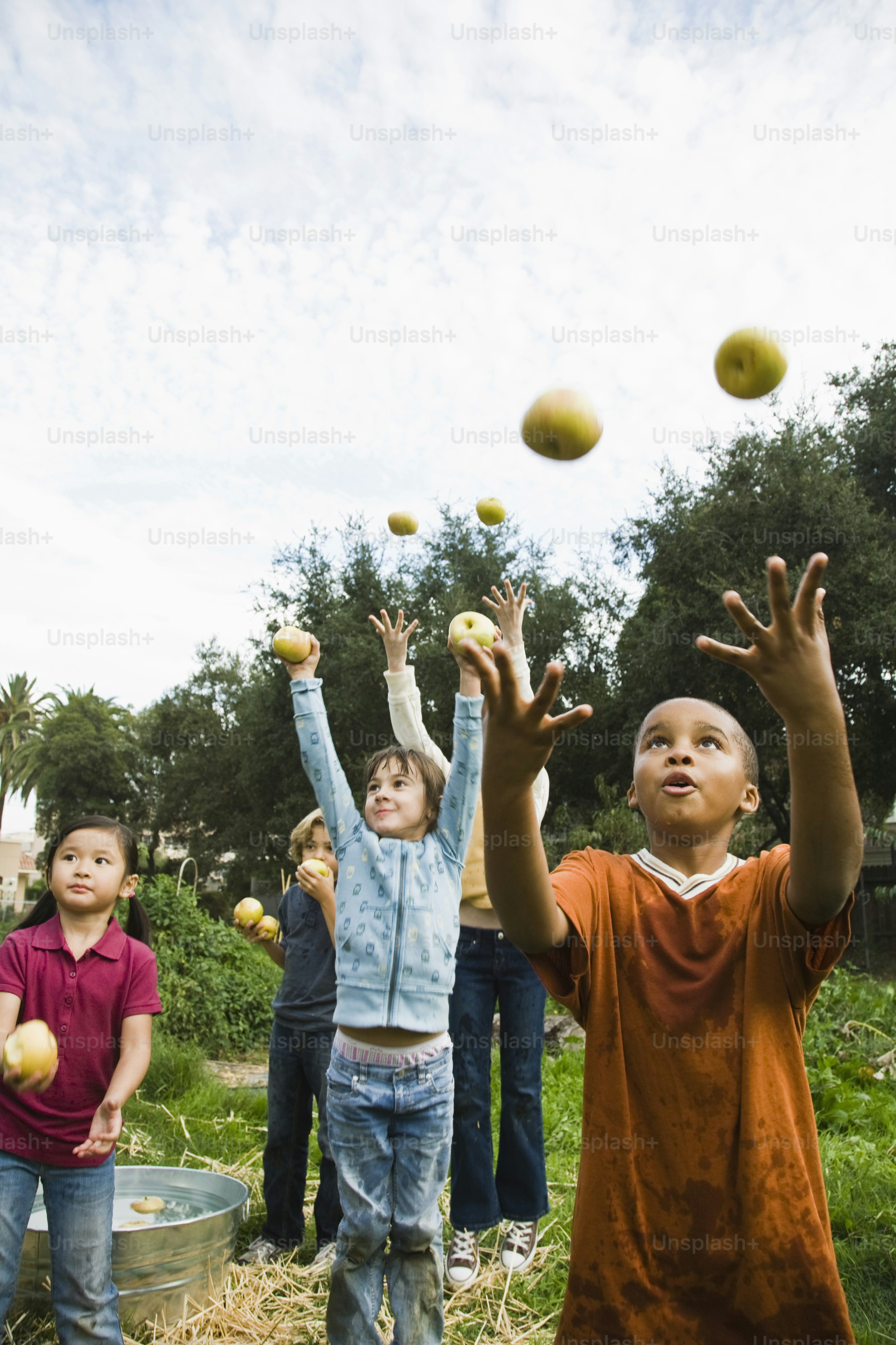 A group of children are throwing apples in the air photo – Juggling ...