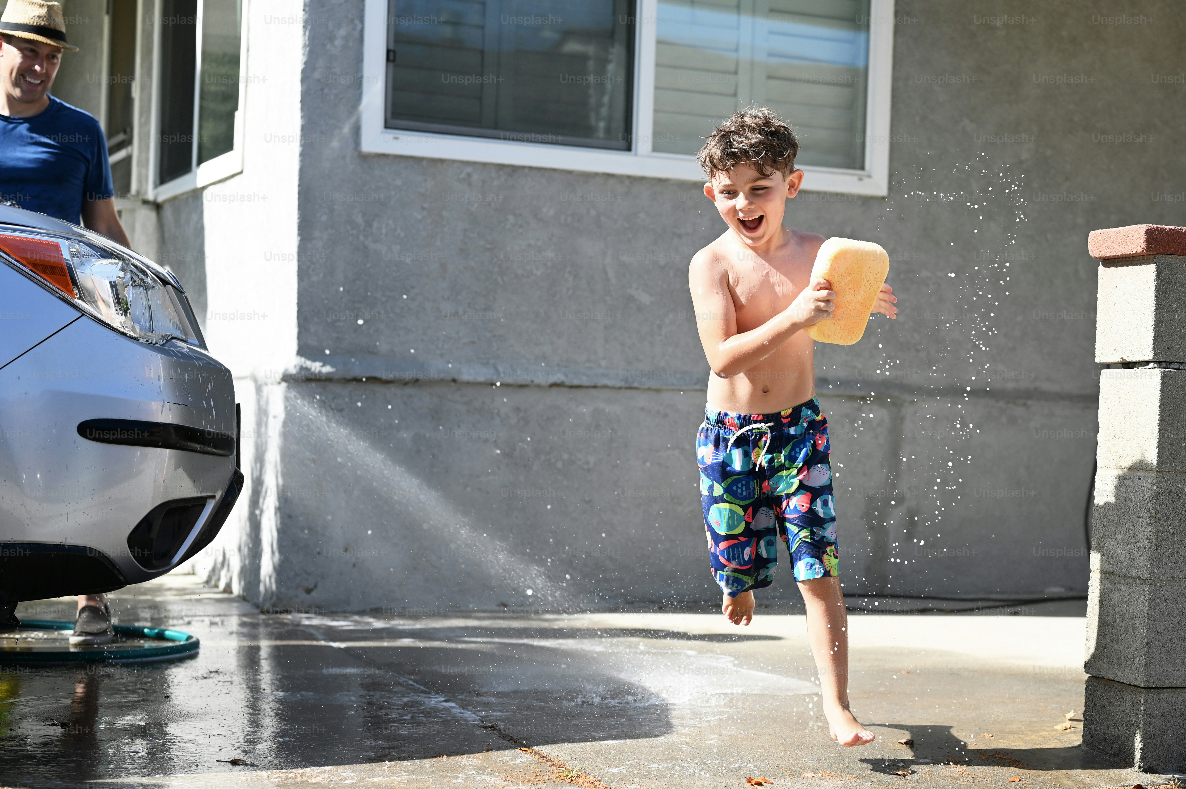 A young boy playing in a sprinkle of water photo – Men Image on Unsplash