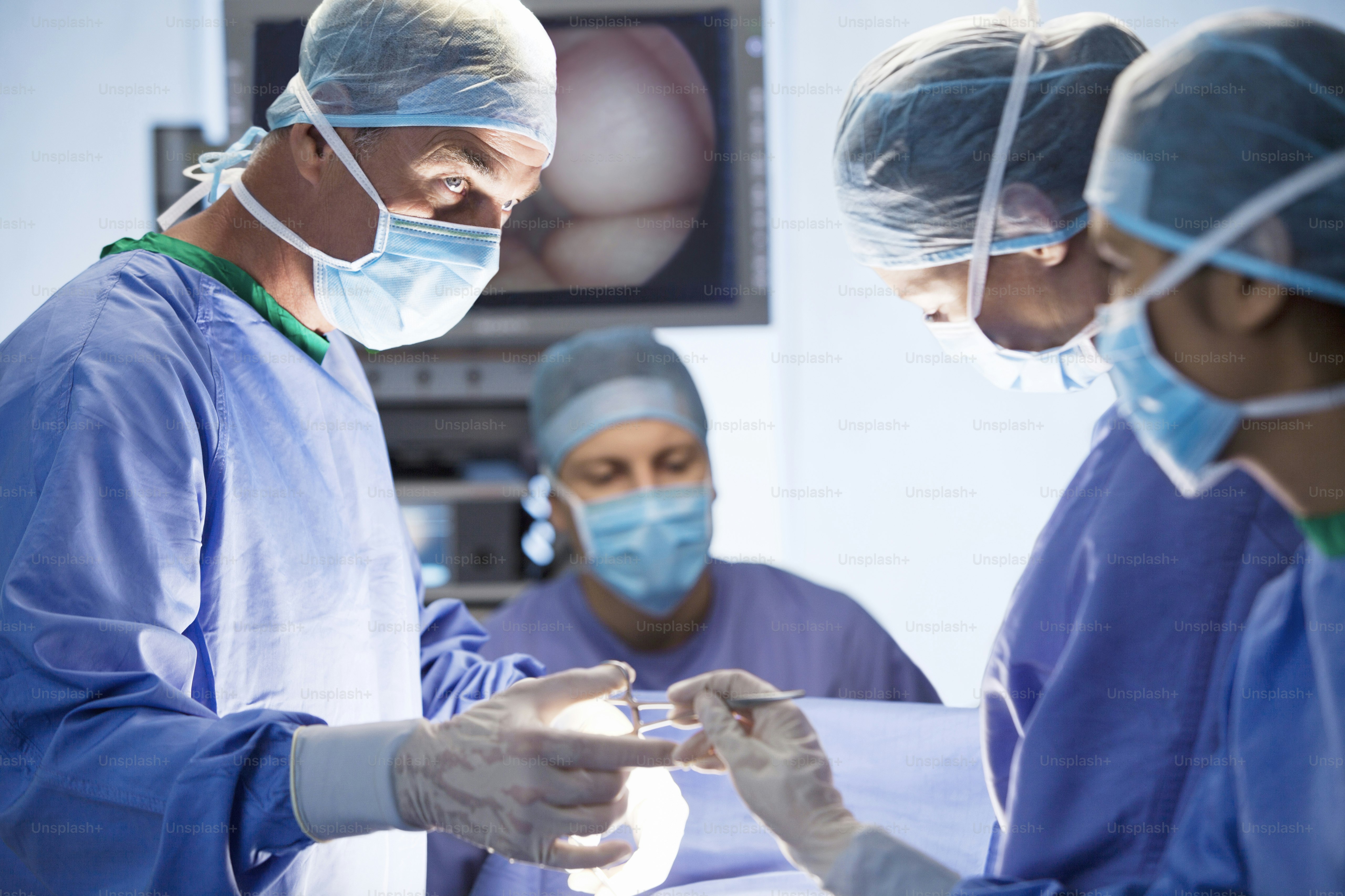 Foto zum Thema Eine Gruppe von Ärzten, die einen Patienten operieren ...