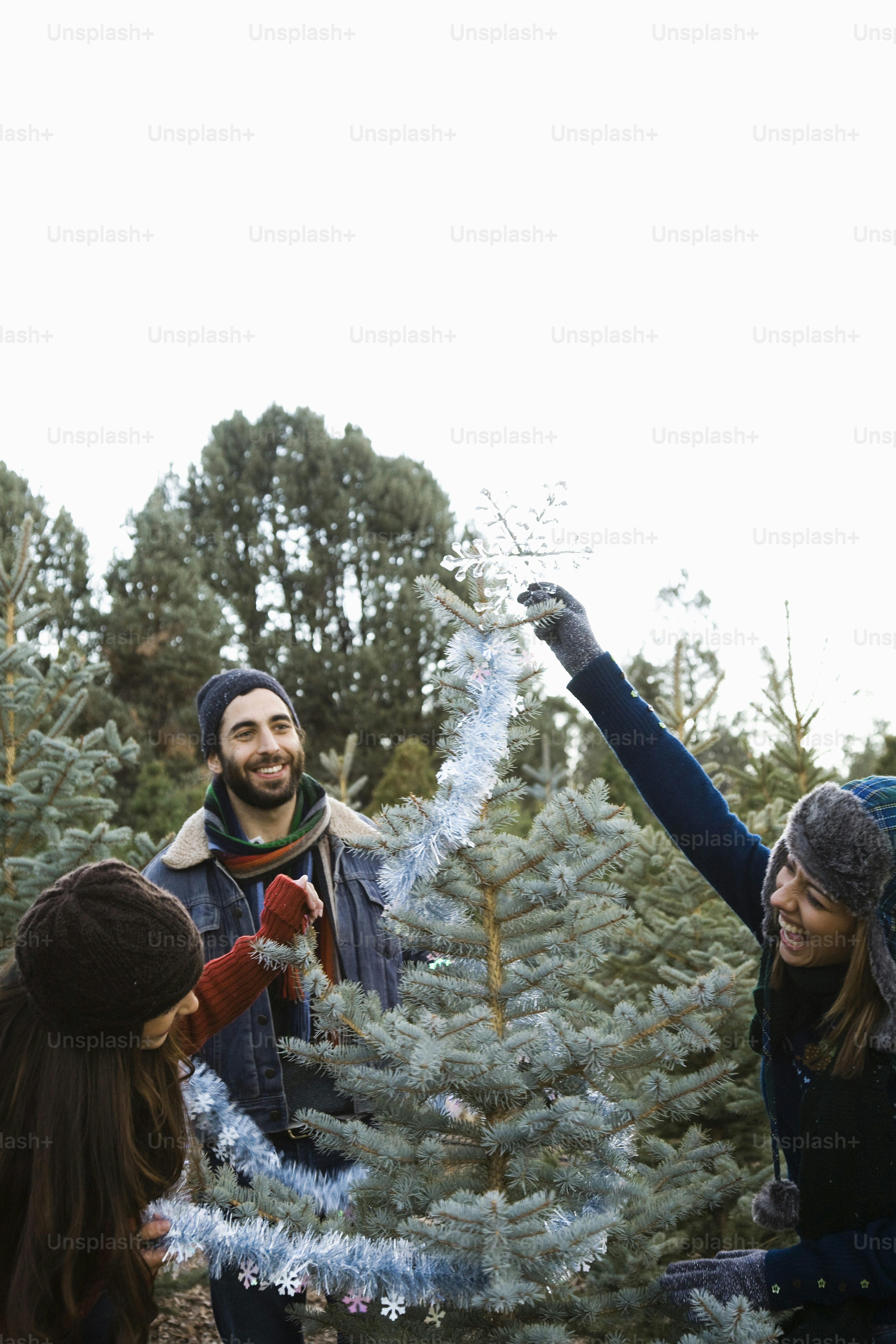 A group of people standing around a christmas tree photo – Christmas ...