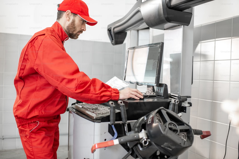 Foto Mecánico de automóviles con uniforme rojo que trabaja con una ... Foto Mecánico de automóviles con uniforme rojo que trabaja con una ...