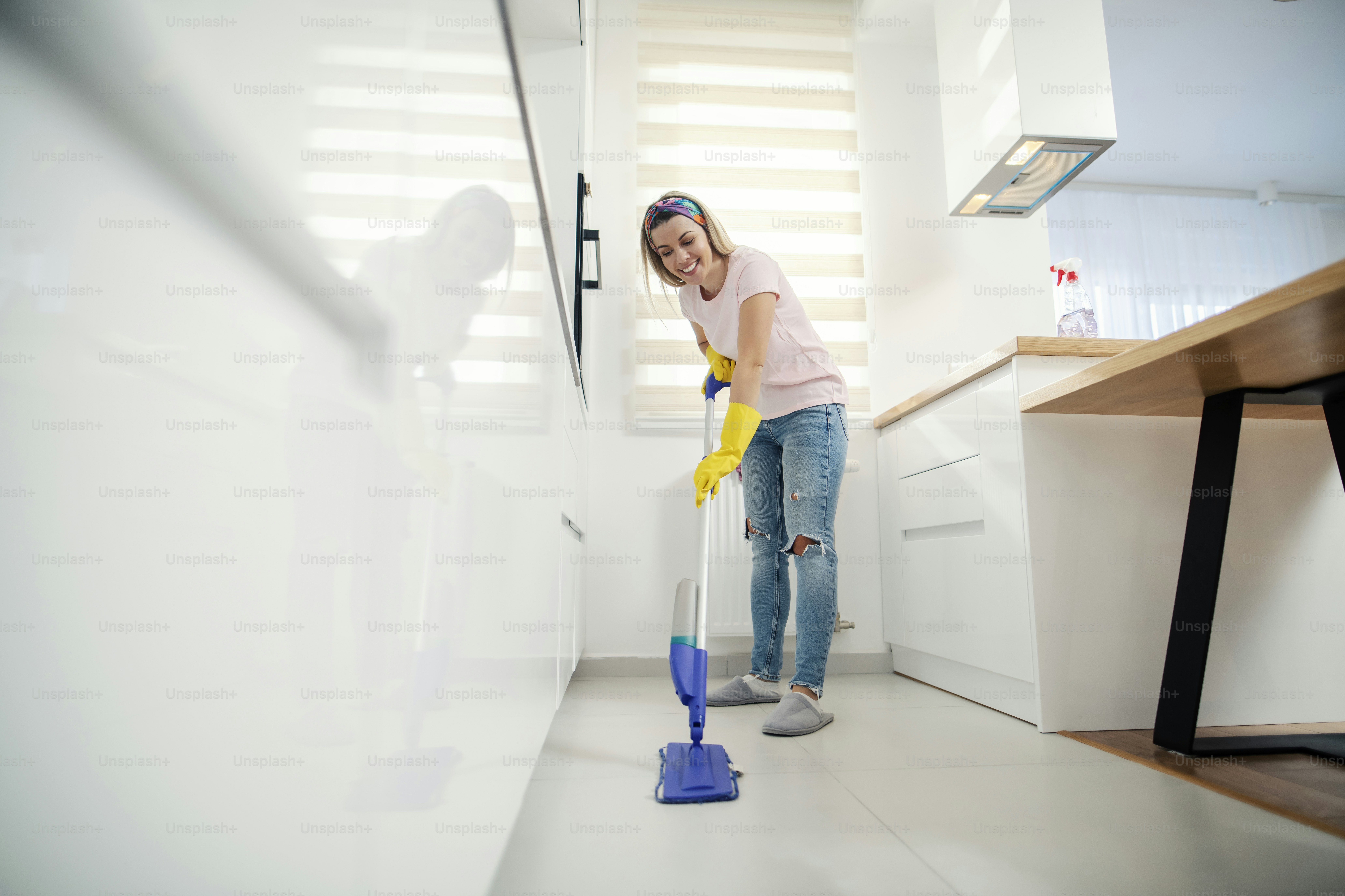 A smiling housewife mopping kitchen floor at home. photo – Mop Image on ...