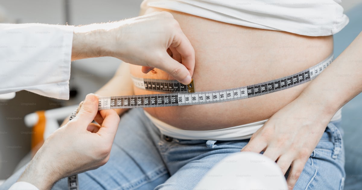 의사가 건강 검진 중 테이프로 임산부의 배를 측정 복부에 초점을 맞춘 얼굴 없이 잘린 보기 사진 Unsplash의 측정 이미지