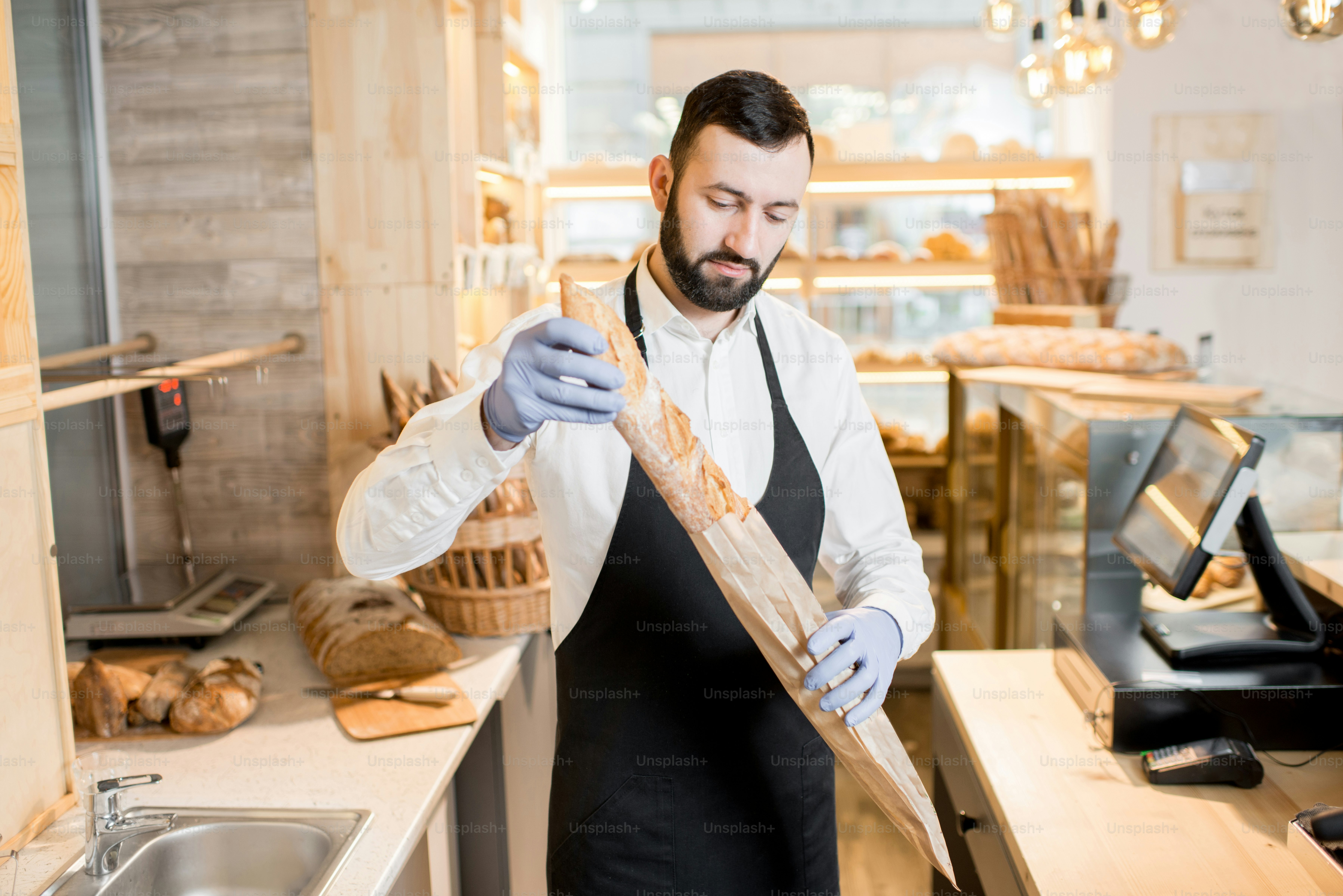 Portrait of a bread seller standing with baguette in the beautiful ...