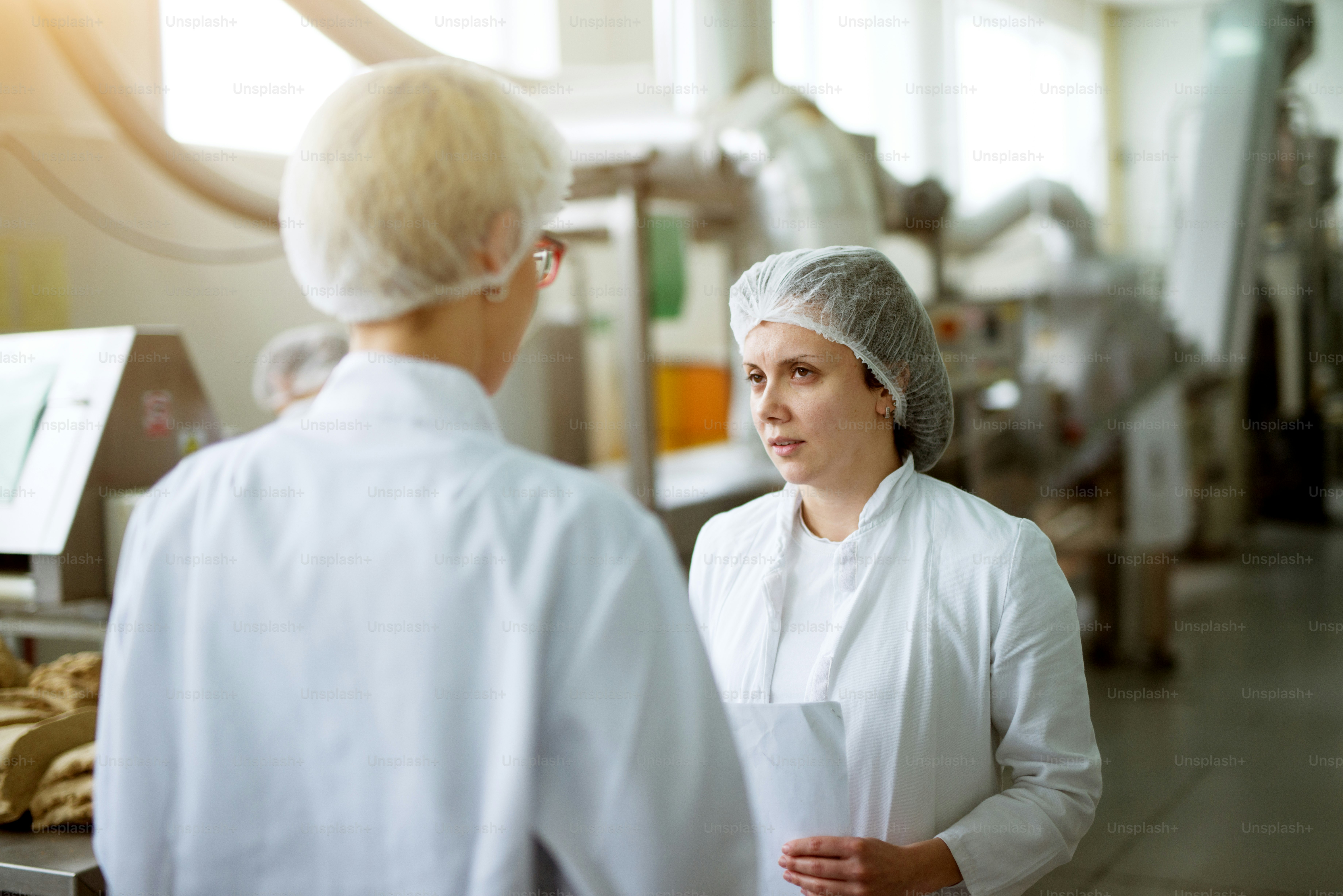 A worried young female worker is explaining a problem to her female ...
