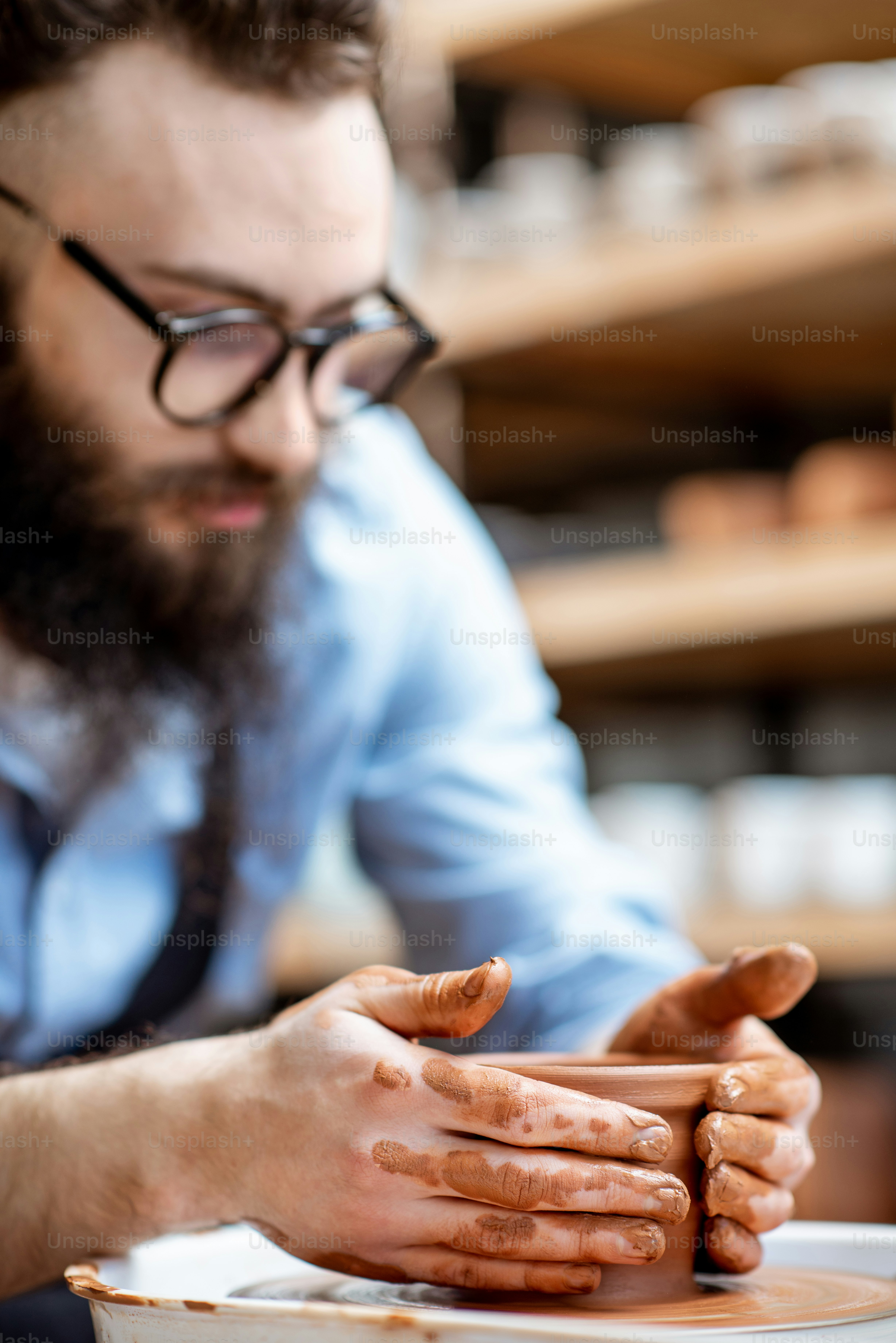 Handsome man as a potter worker in apron making clay jugs on the ...