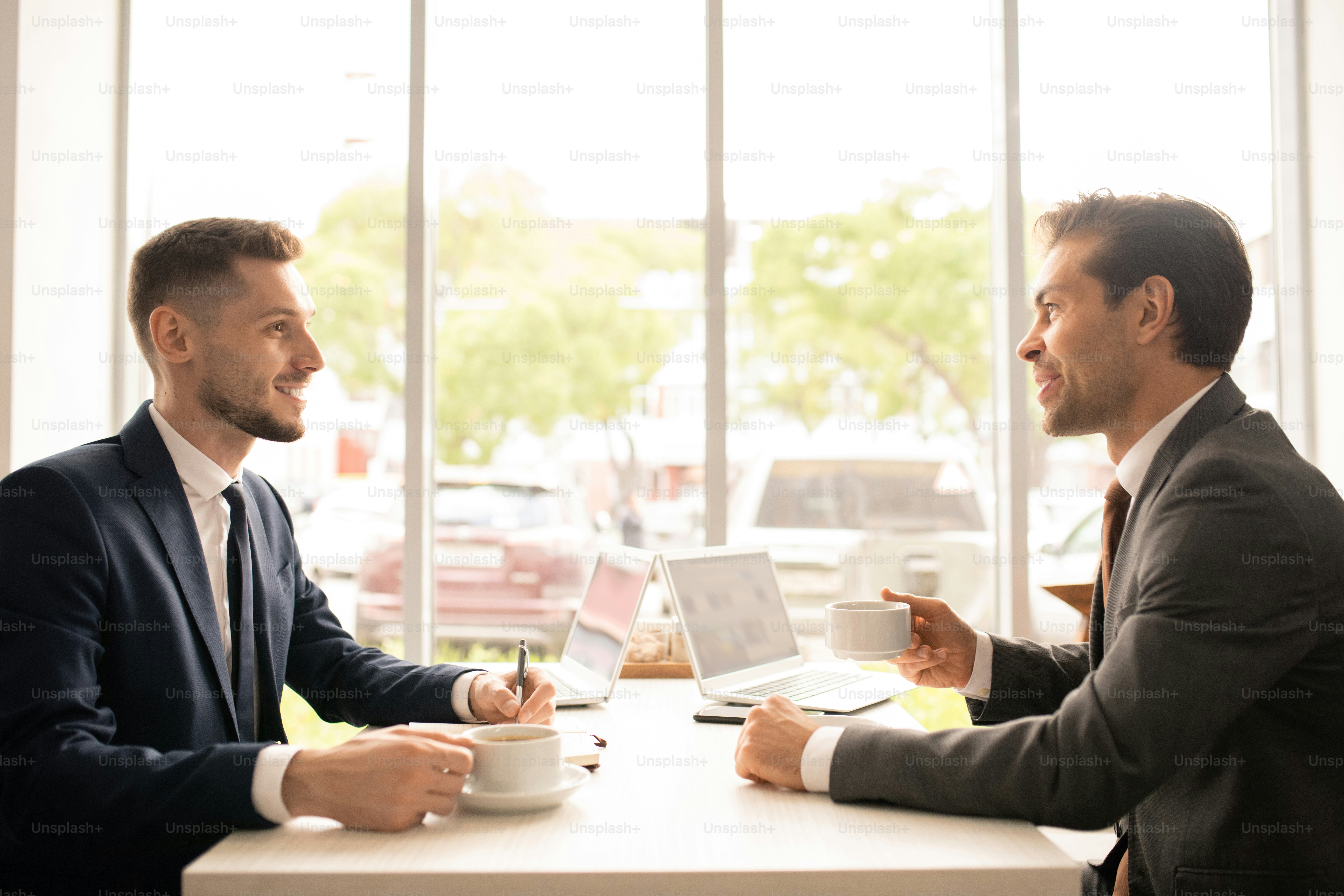 Two young successful colleagues in foralwear having tea and discussing ...