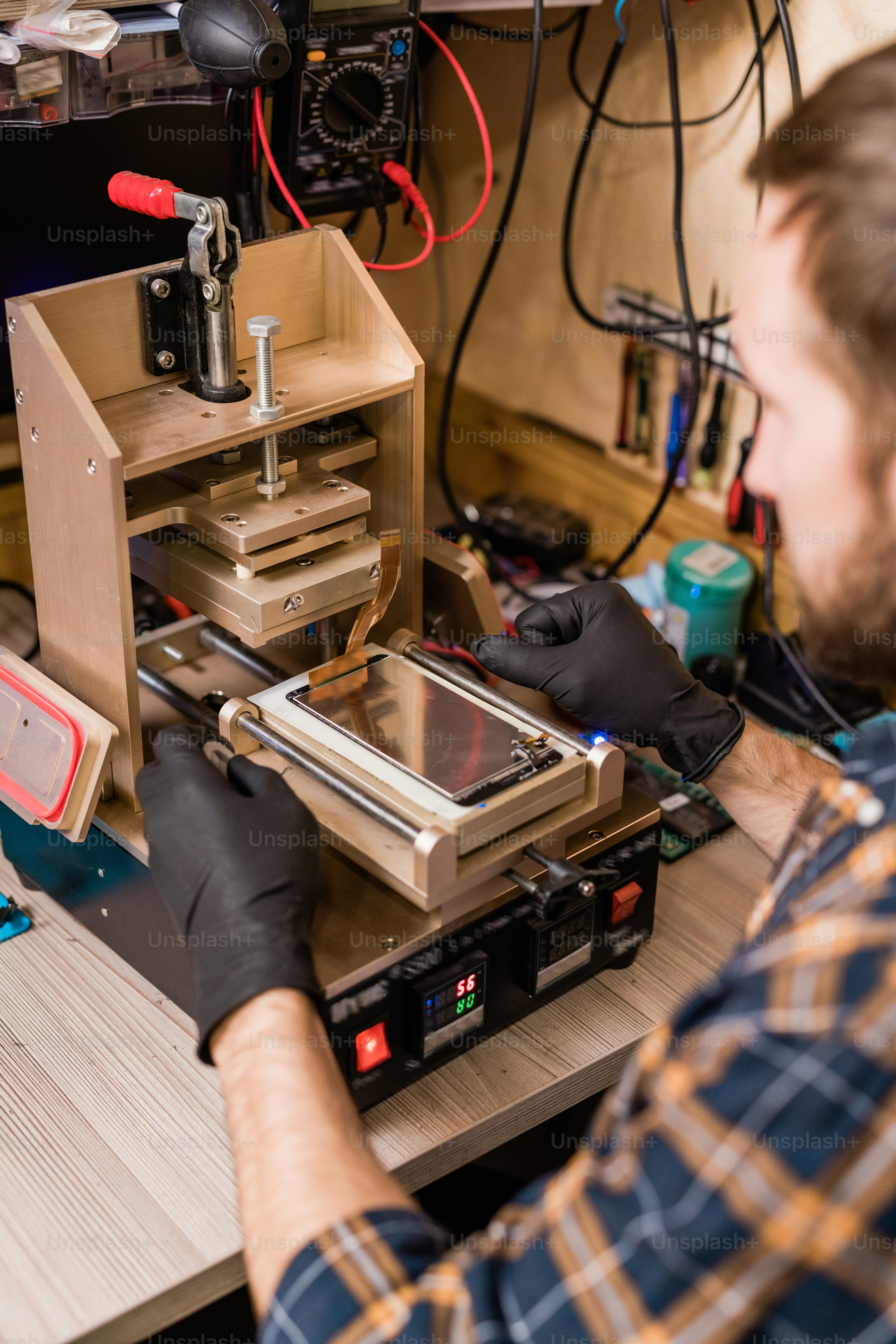 Professional repairman in protective gloves using equipment for gadget ...