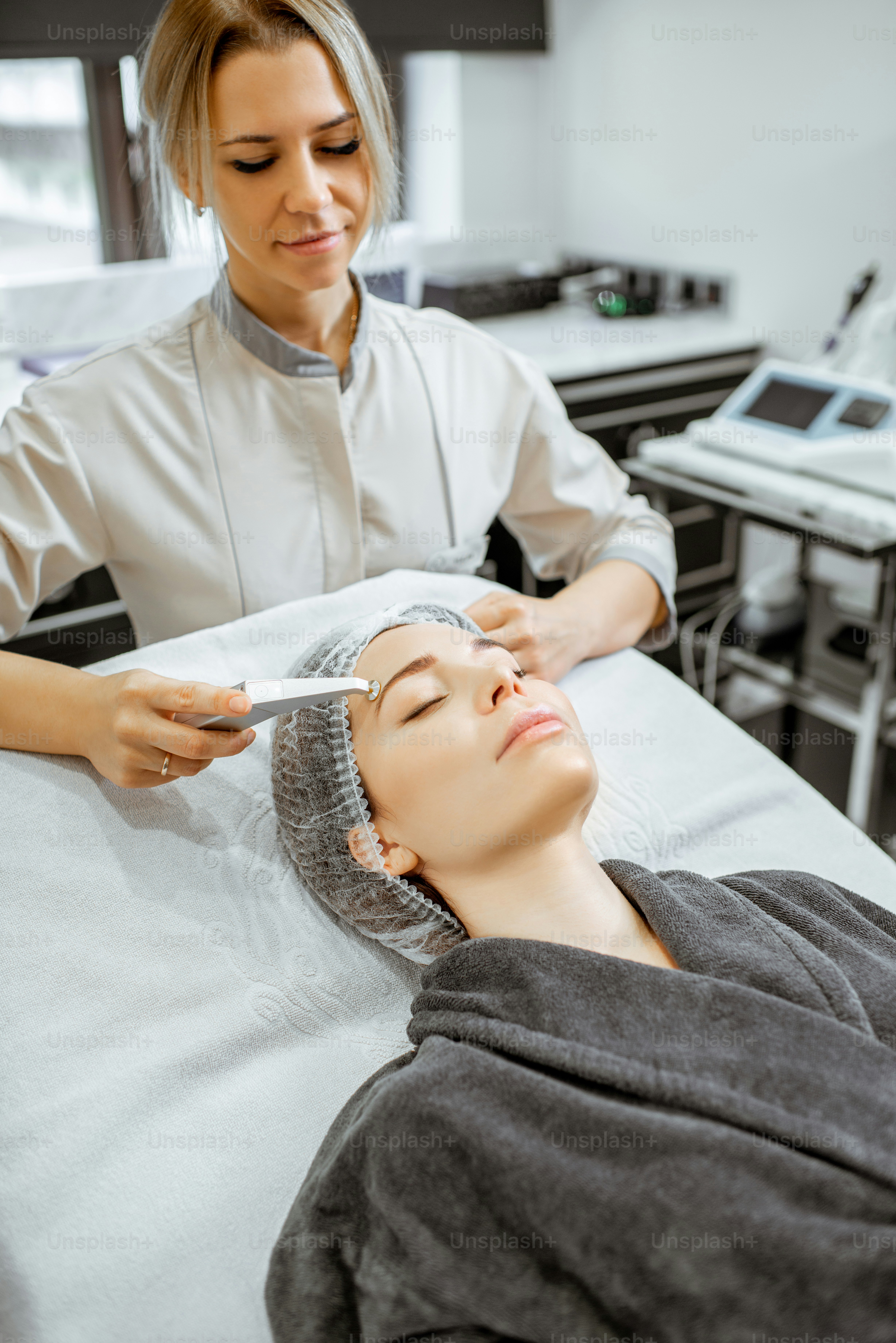 Female cosmetologist making vacuum hydro peeling to a woman at the ...