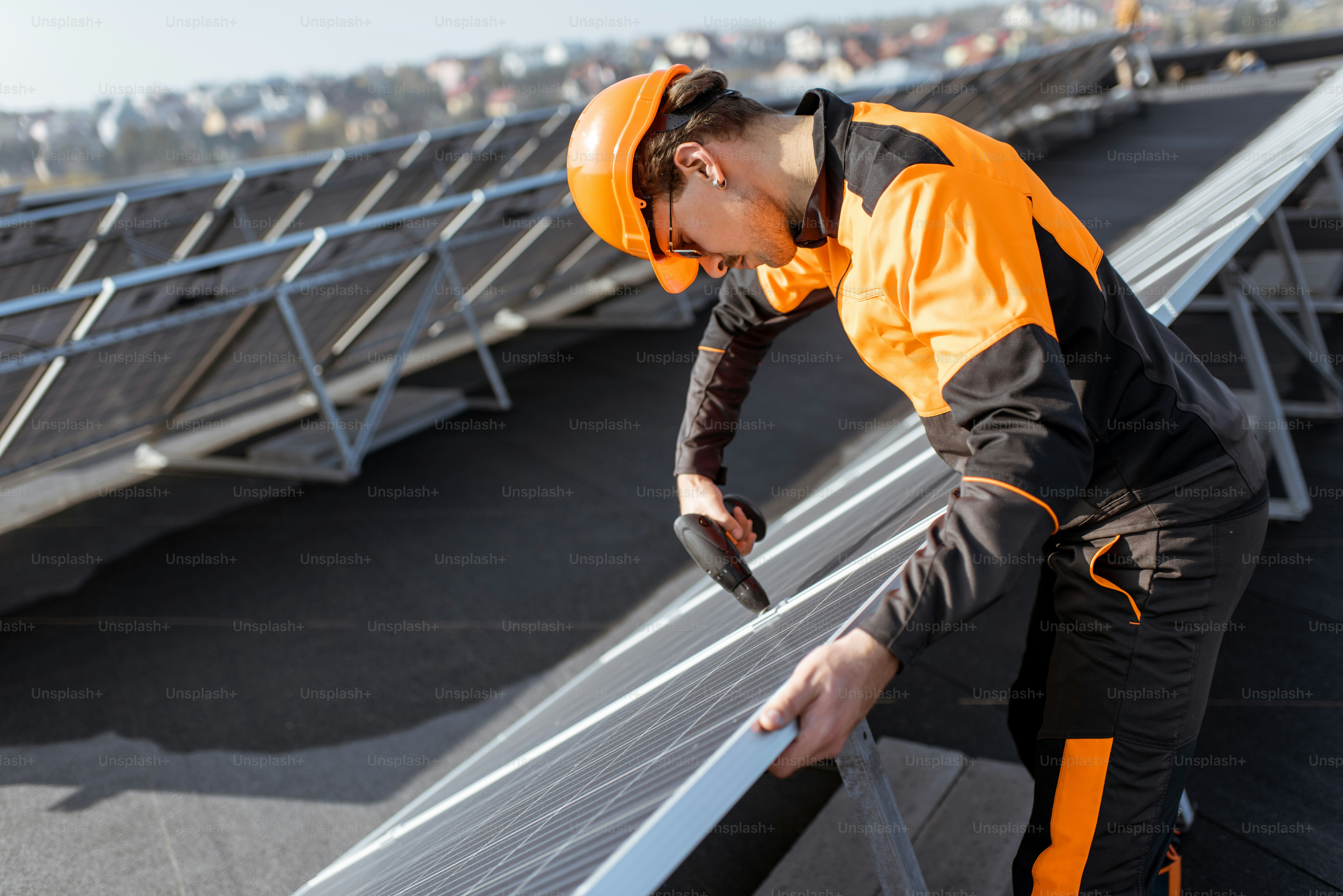 Well-equipped worker in protective orange clothing servicing solar ...