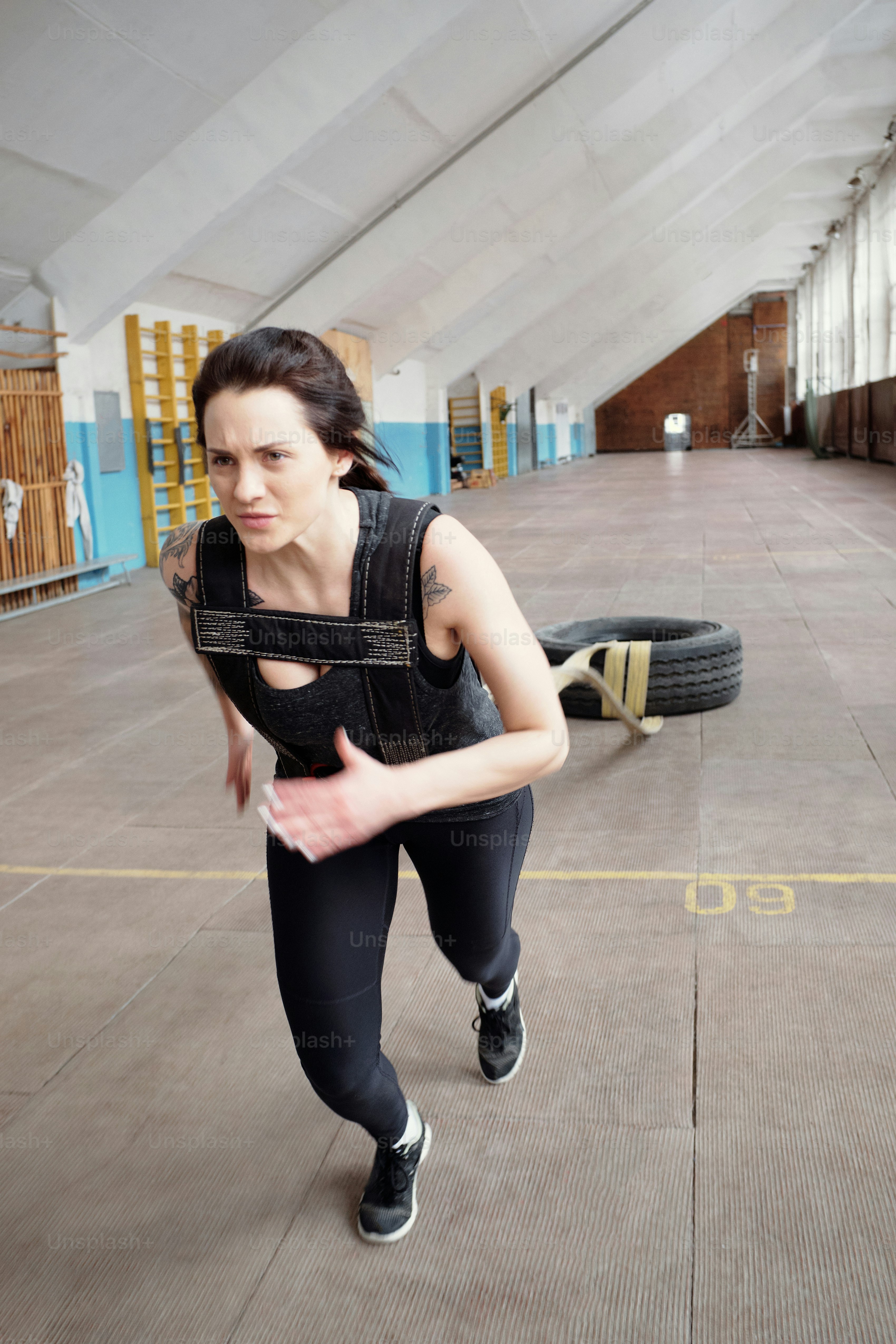 Tire pulling workout. Young attractive Caucasian sportswoman dragging ...