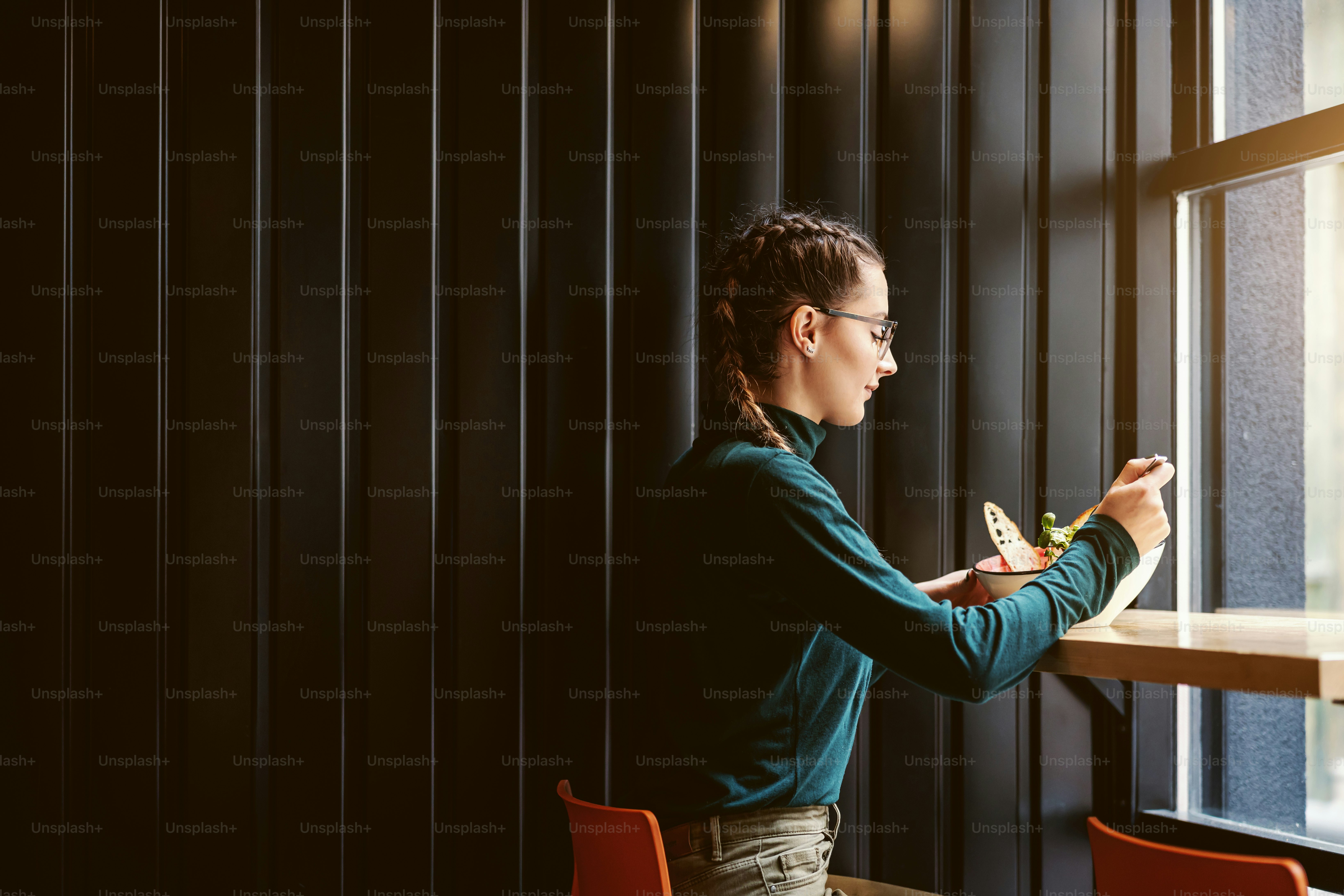 Side view of geeky girl with healthy habits sitting in restaurant near ...