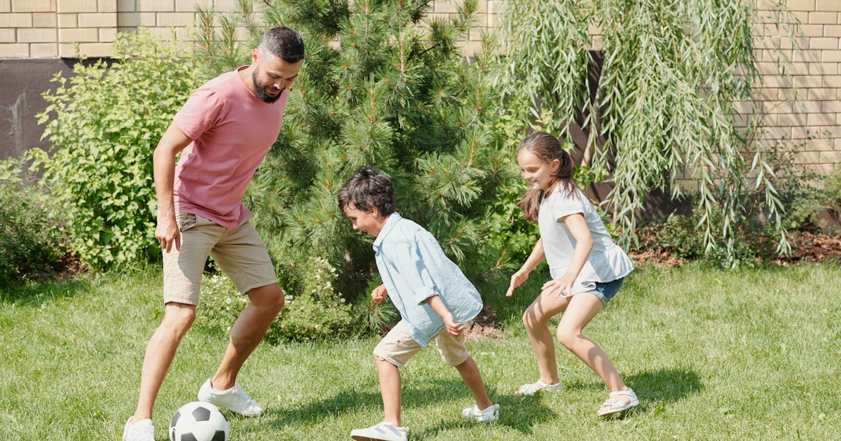 Père Moderne Jouant Au Football Avec Son Fils Et Sa Fille Sur La