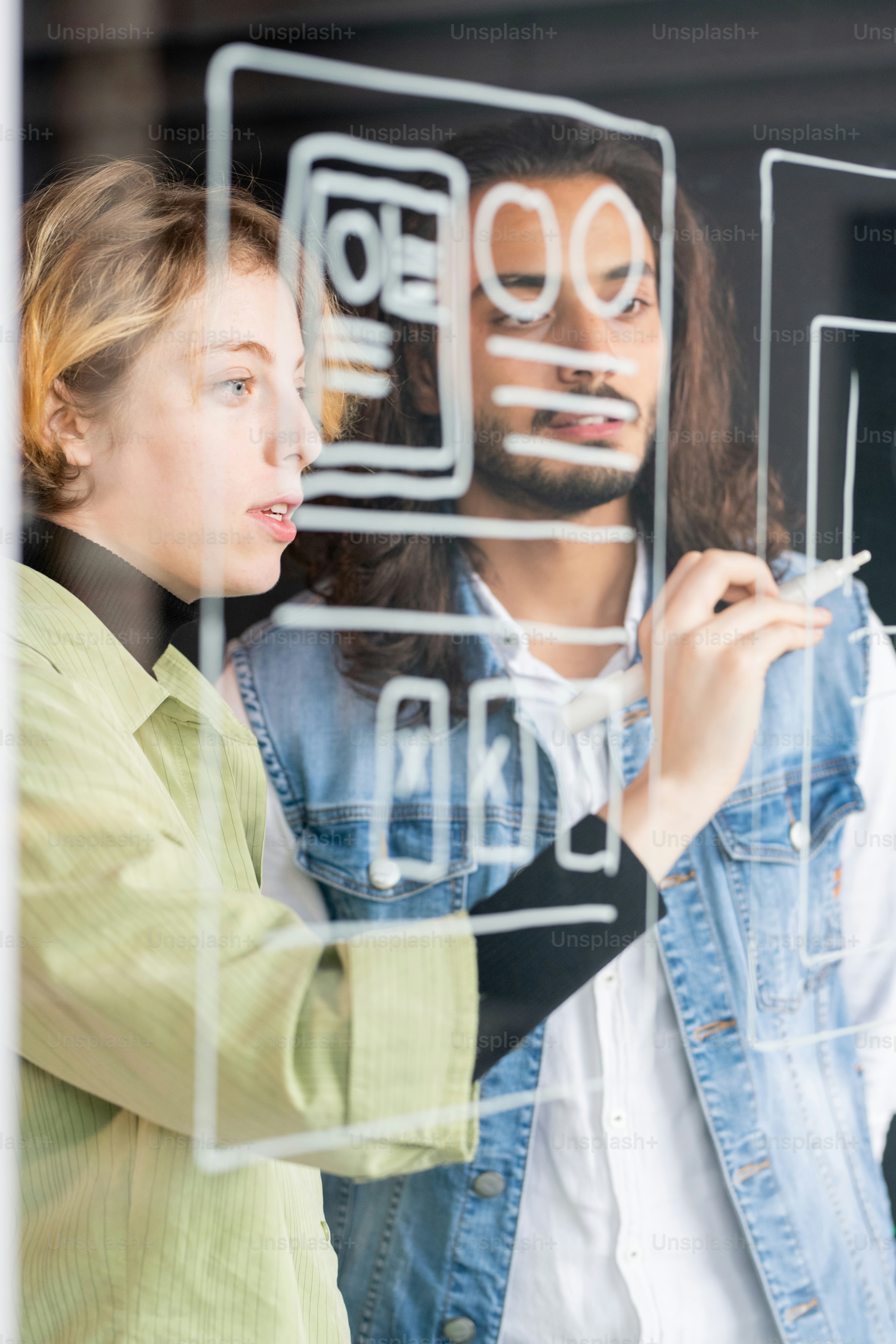 Young confident female software developer pointing at sketch of new ...