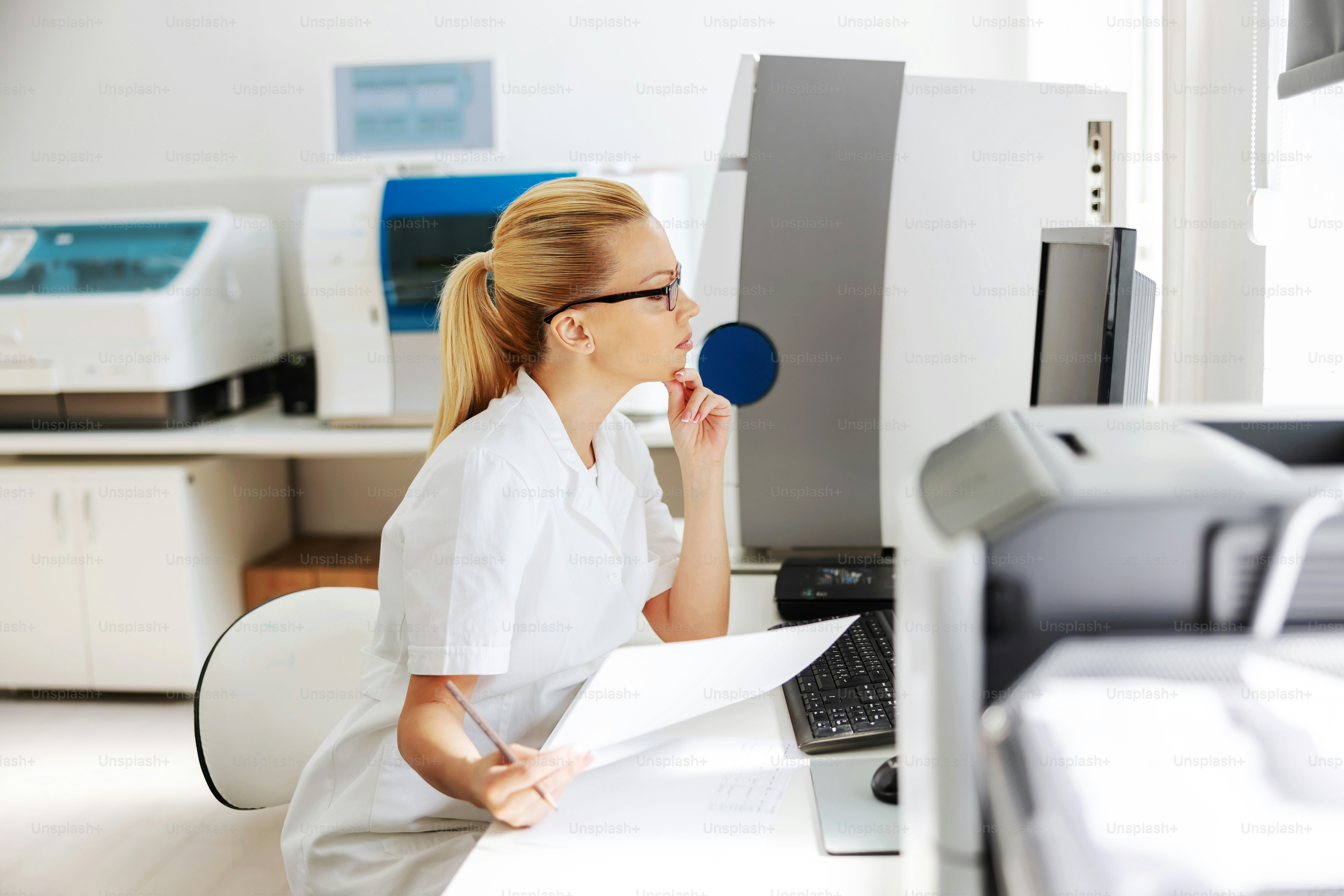 Young blond attractive female lab assistant in sterile white uniform ...