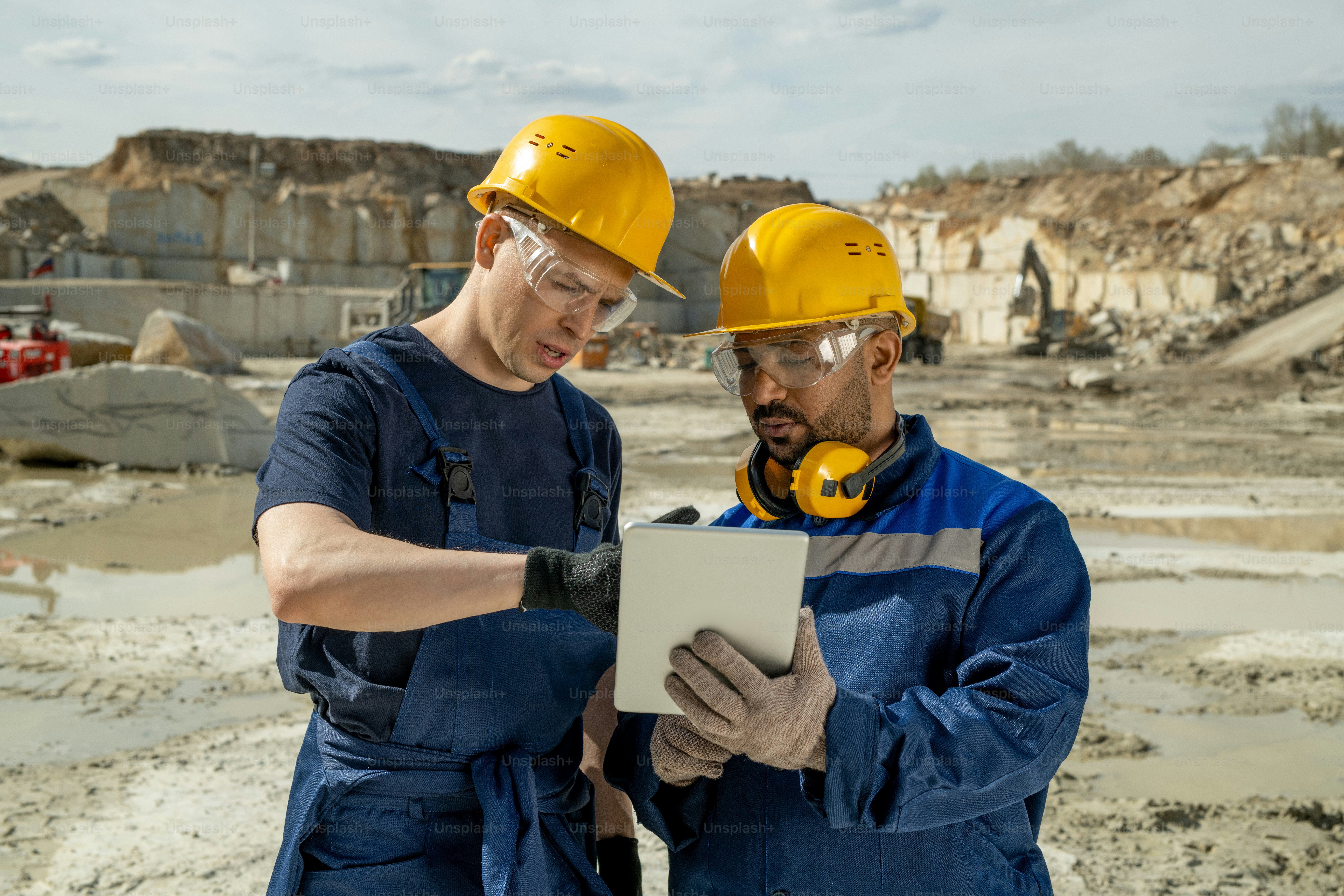 Dos constructores interculturales usando una tableta digital mientras discuten los detalles del ...