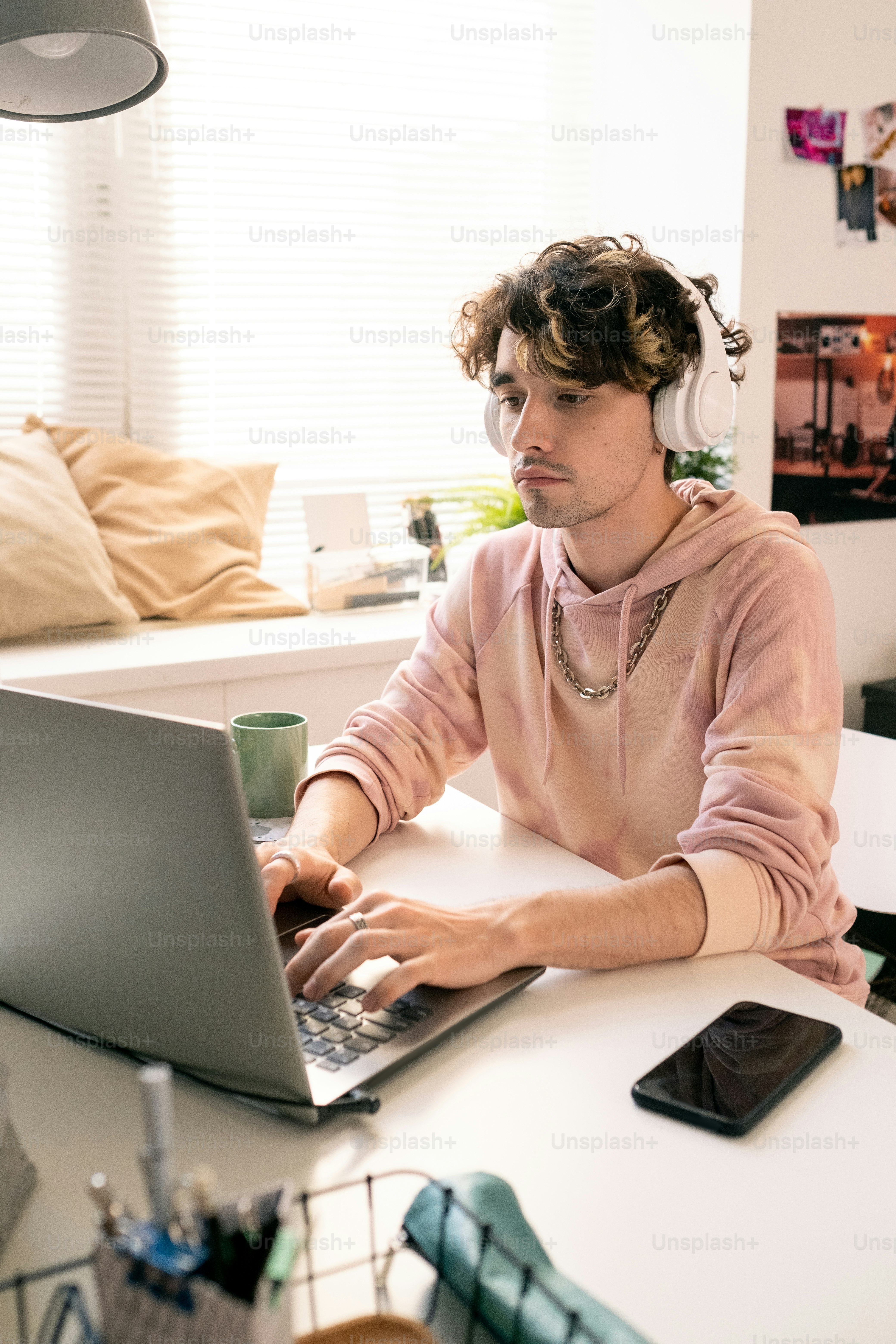 Contemporary guy with headphones looking at laptop display while typing ...