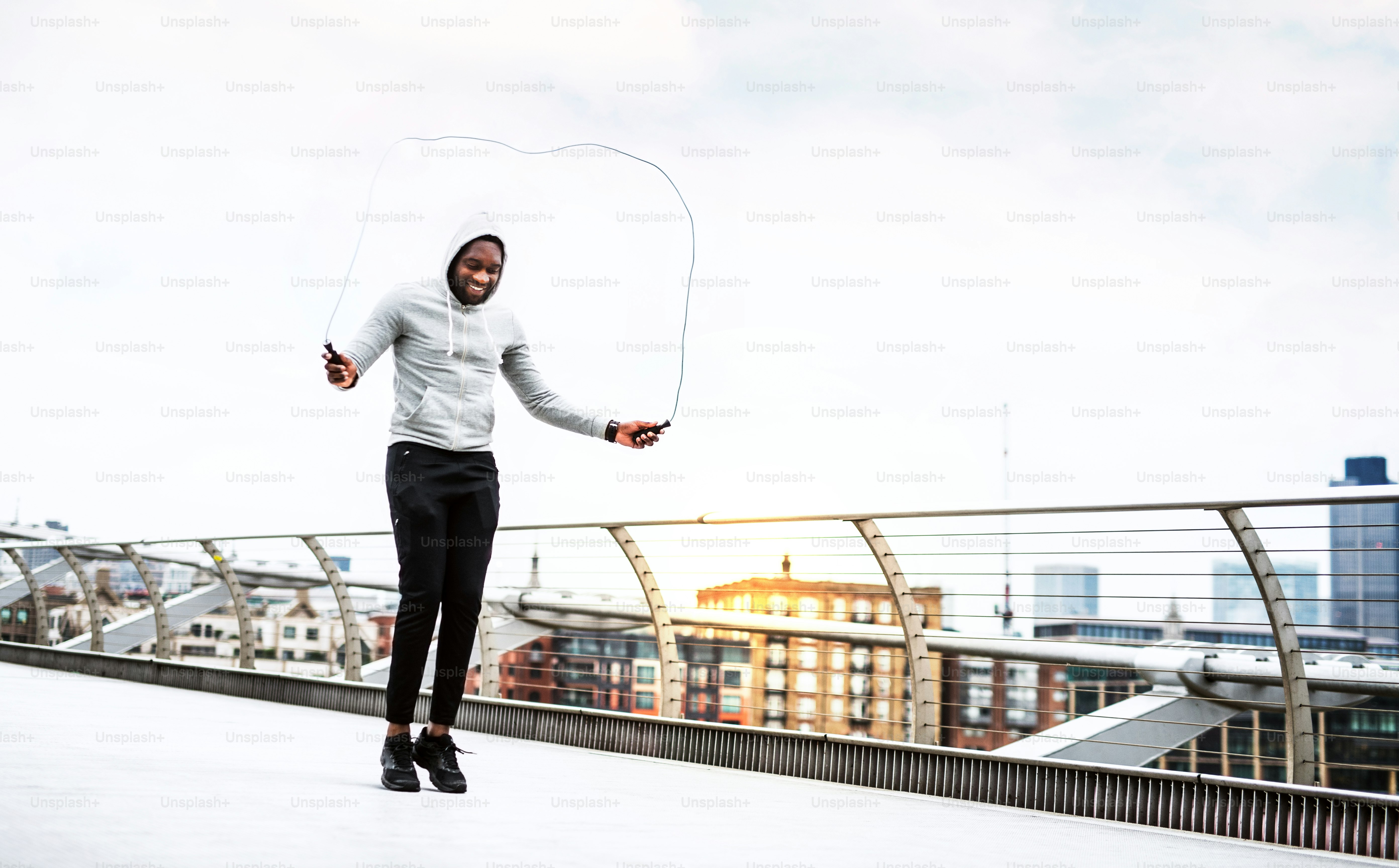 A close-up of a young active black sportsman skipping with a rope in a ...