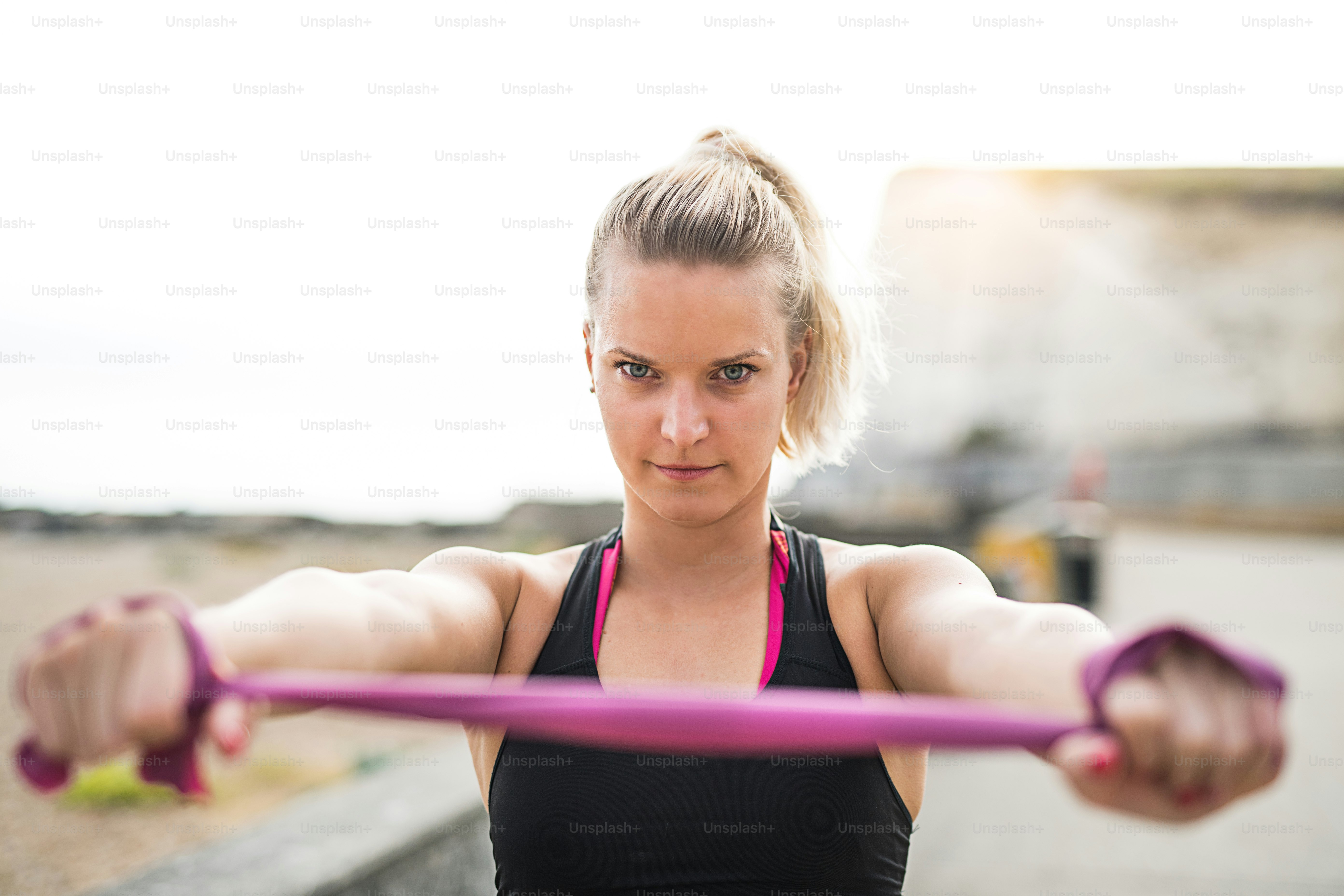 Young sporty woman runner doing exercise with elastic rubber bands ...