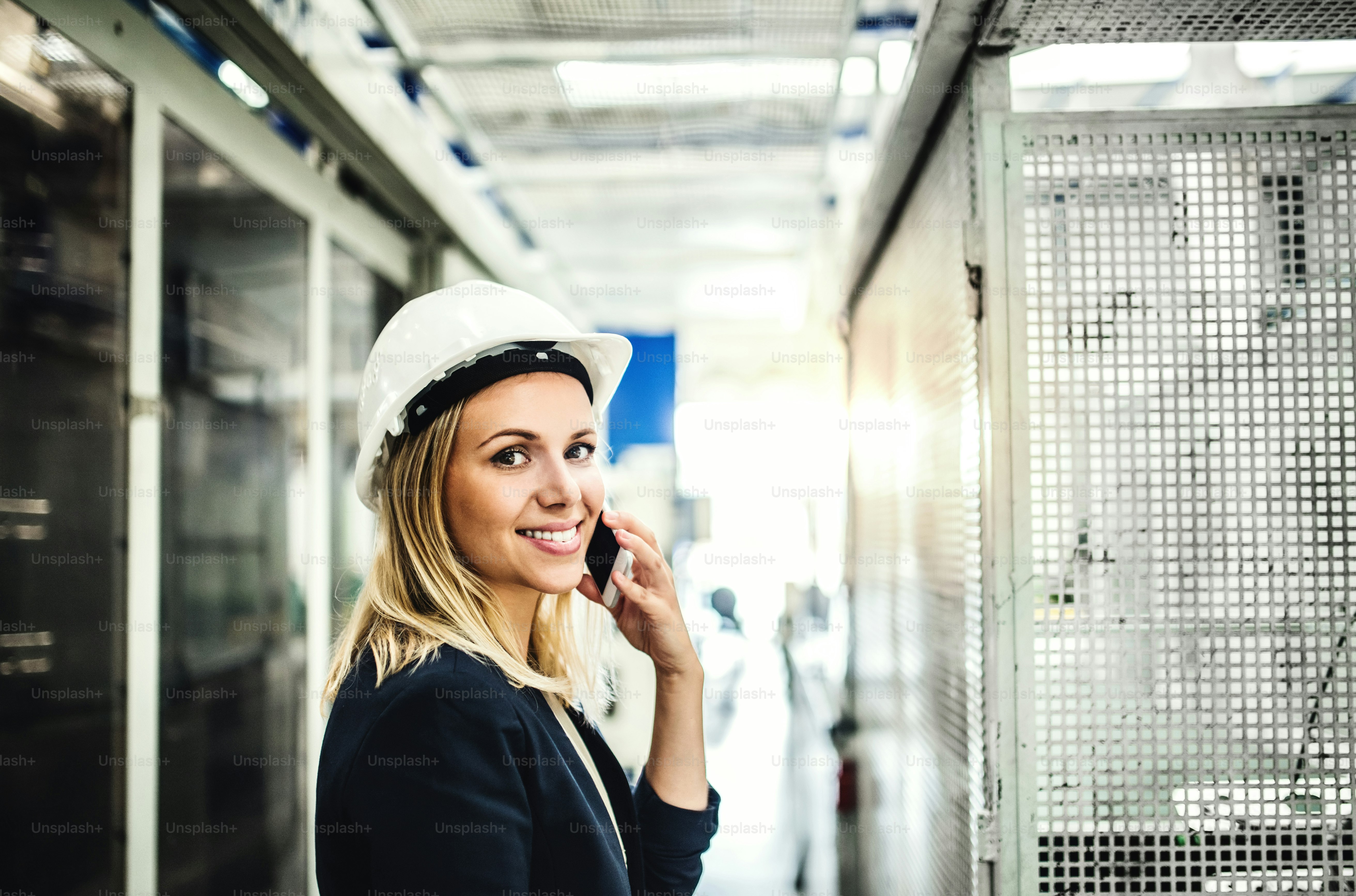 A portrait of a happy industrial woman engineer on the phone, standing ...