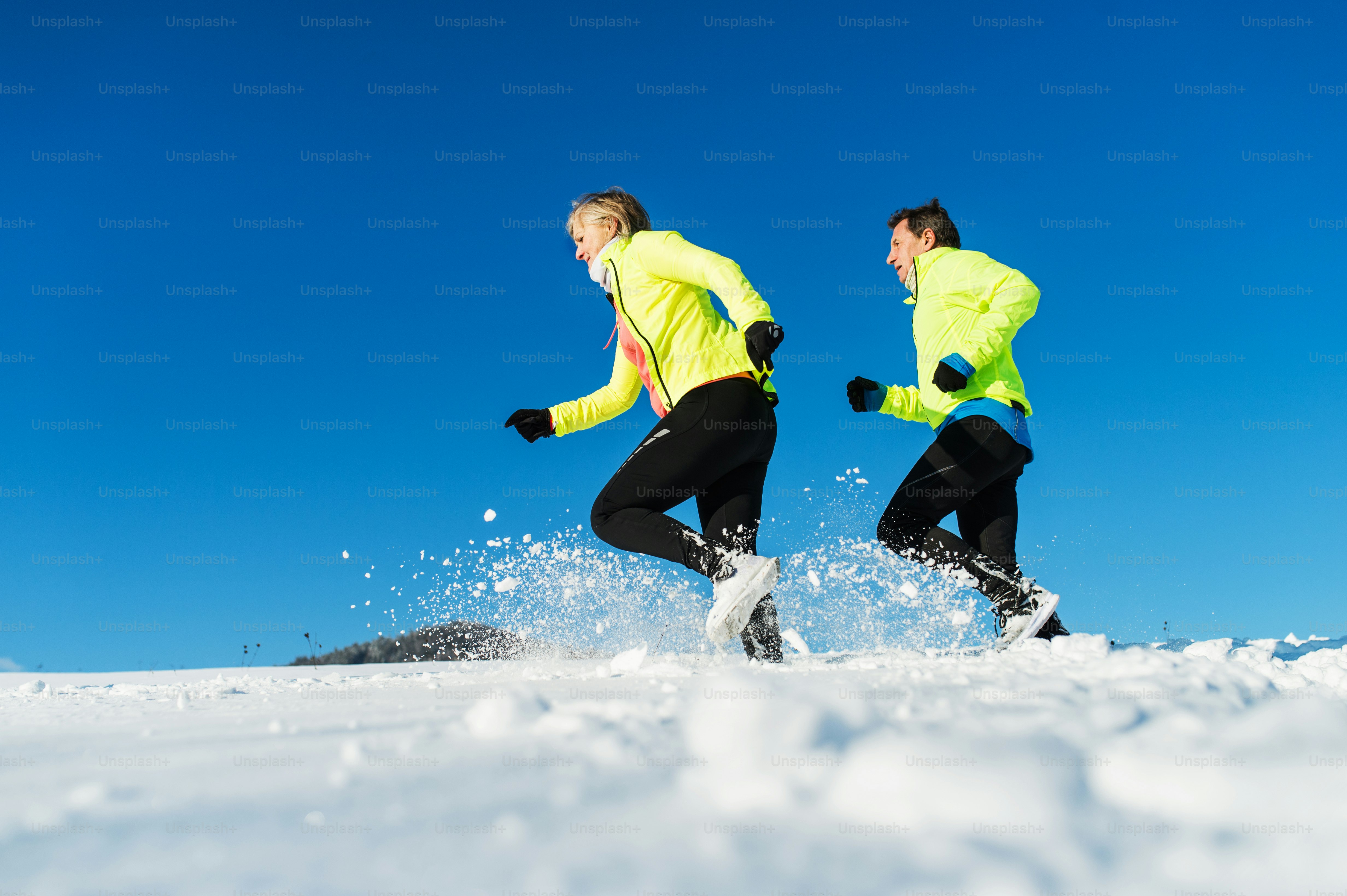 Senior couple runners running in winter nature in snow. Copy space ...
