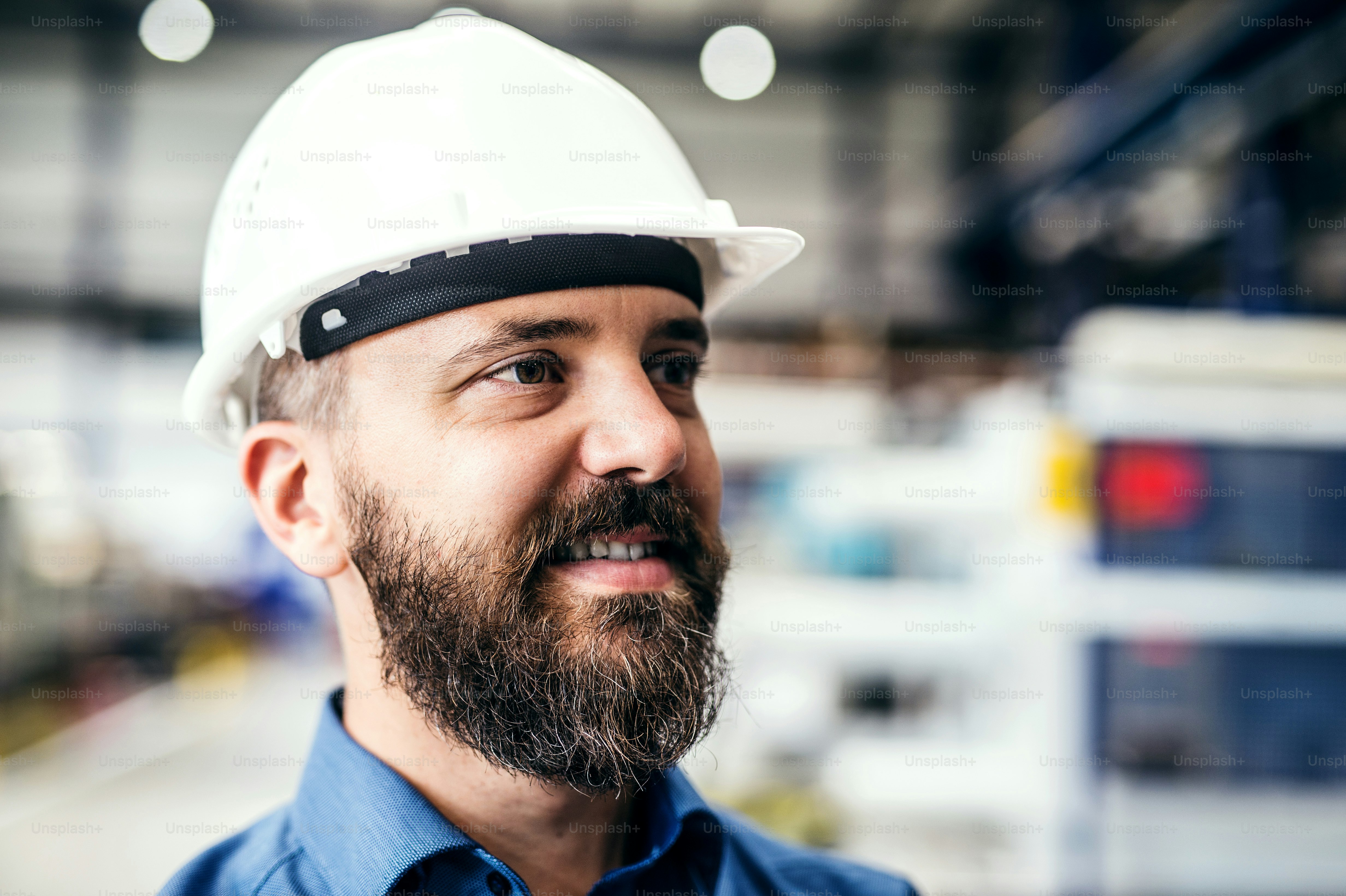 A portrait of a happy industrial man engineer with helmet in a factory ...