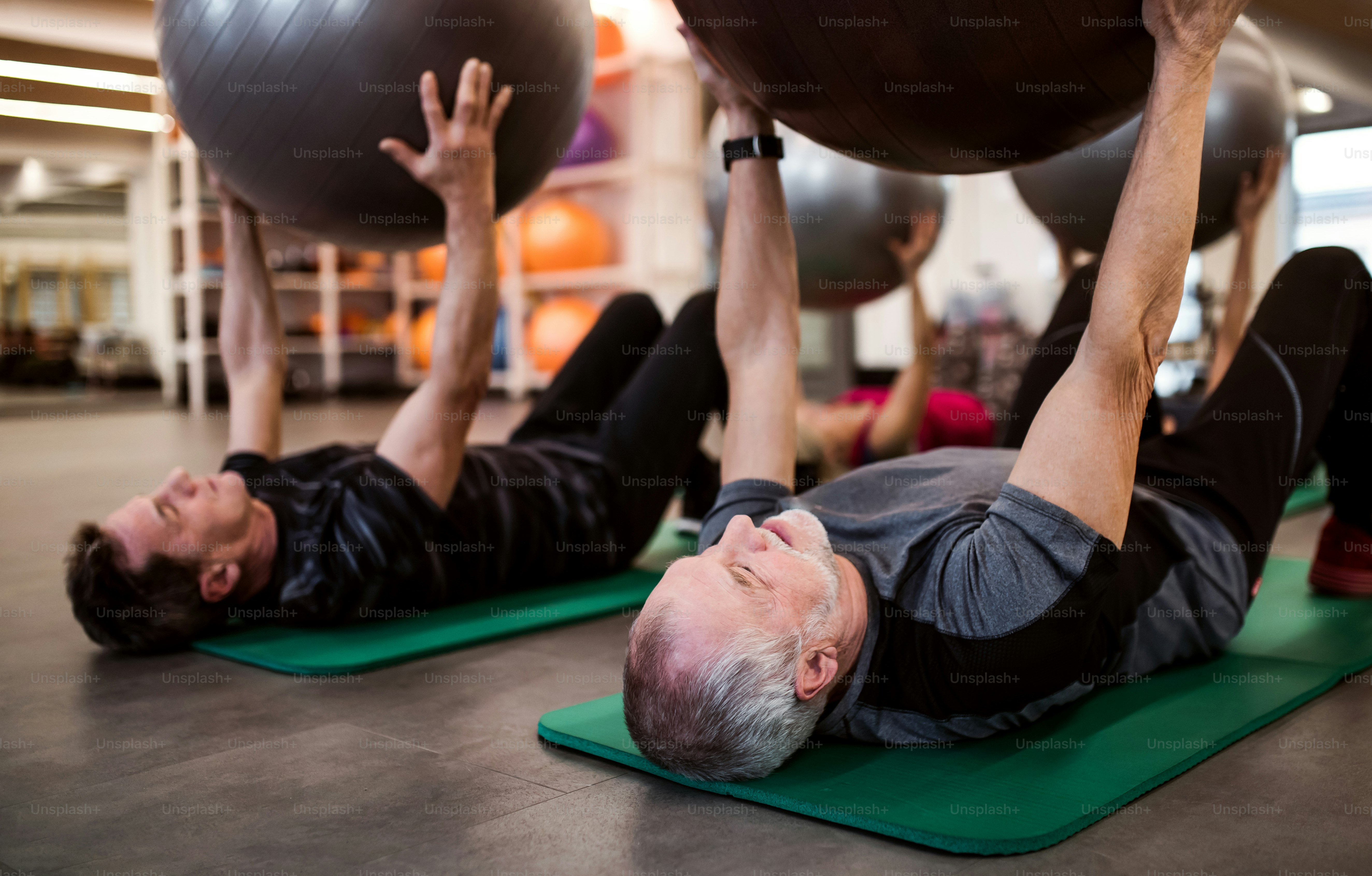 A group of cheerful seniors in gym doing exercise with fit balls ...