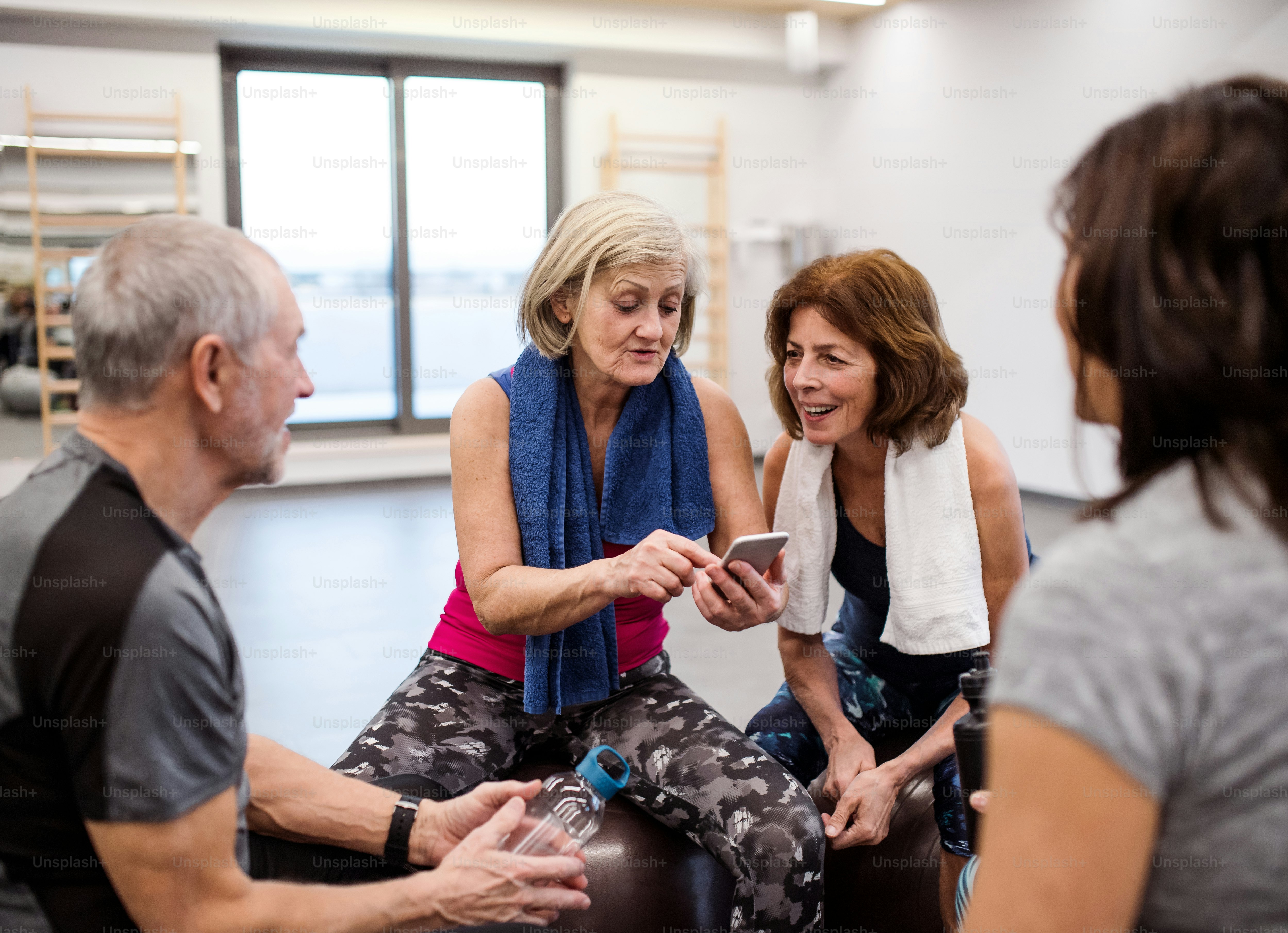 A group of cheerful seniors in gym doing exercise on fit balls ...