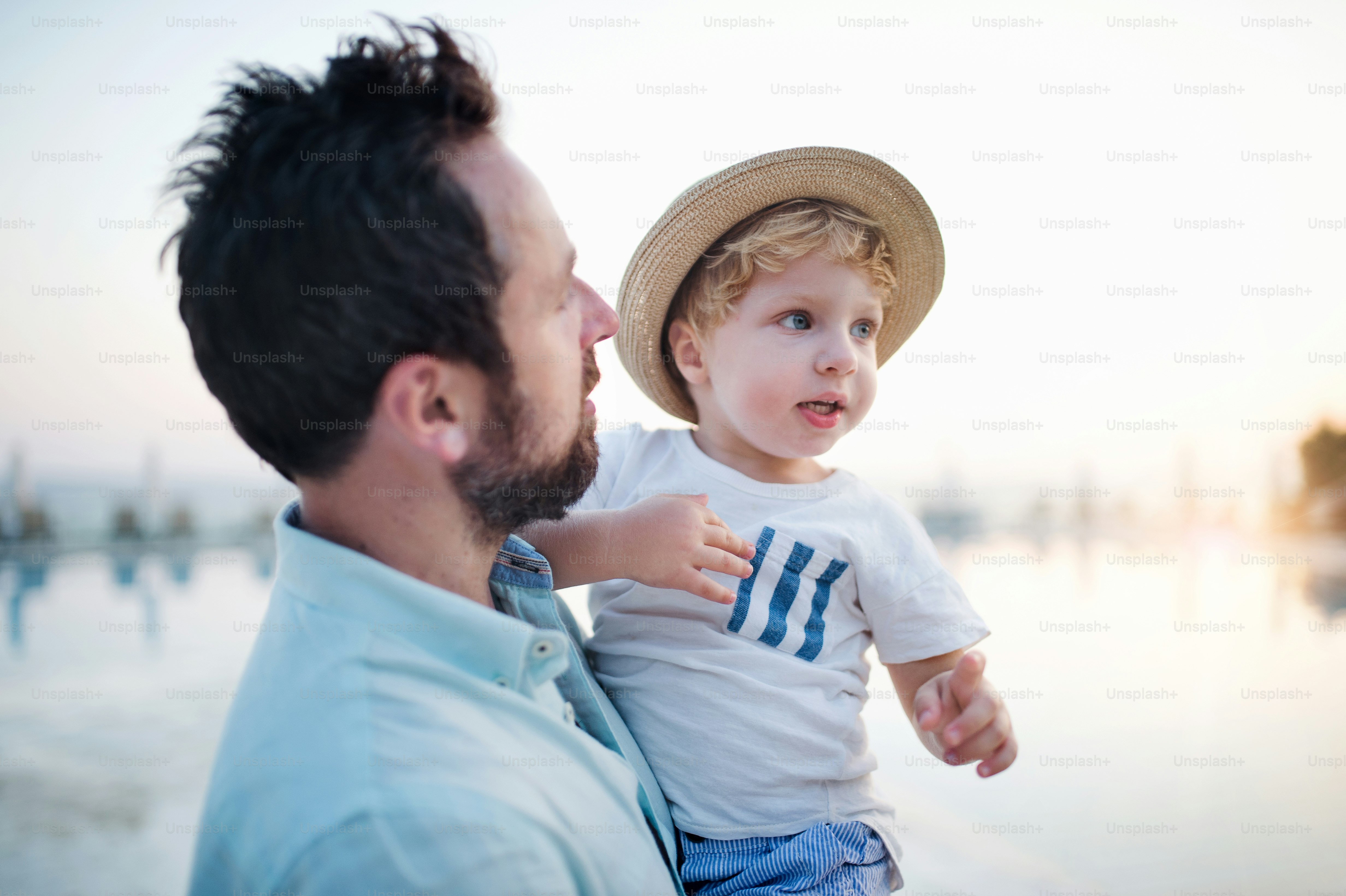 A mature father holding a toddler boy on beach on summer holiday. photo ...